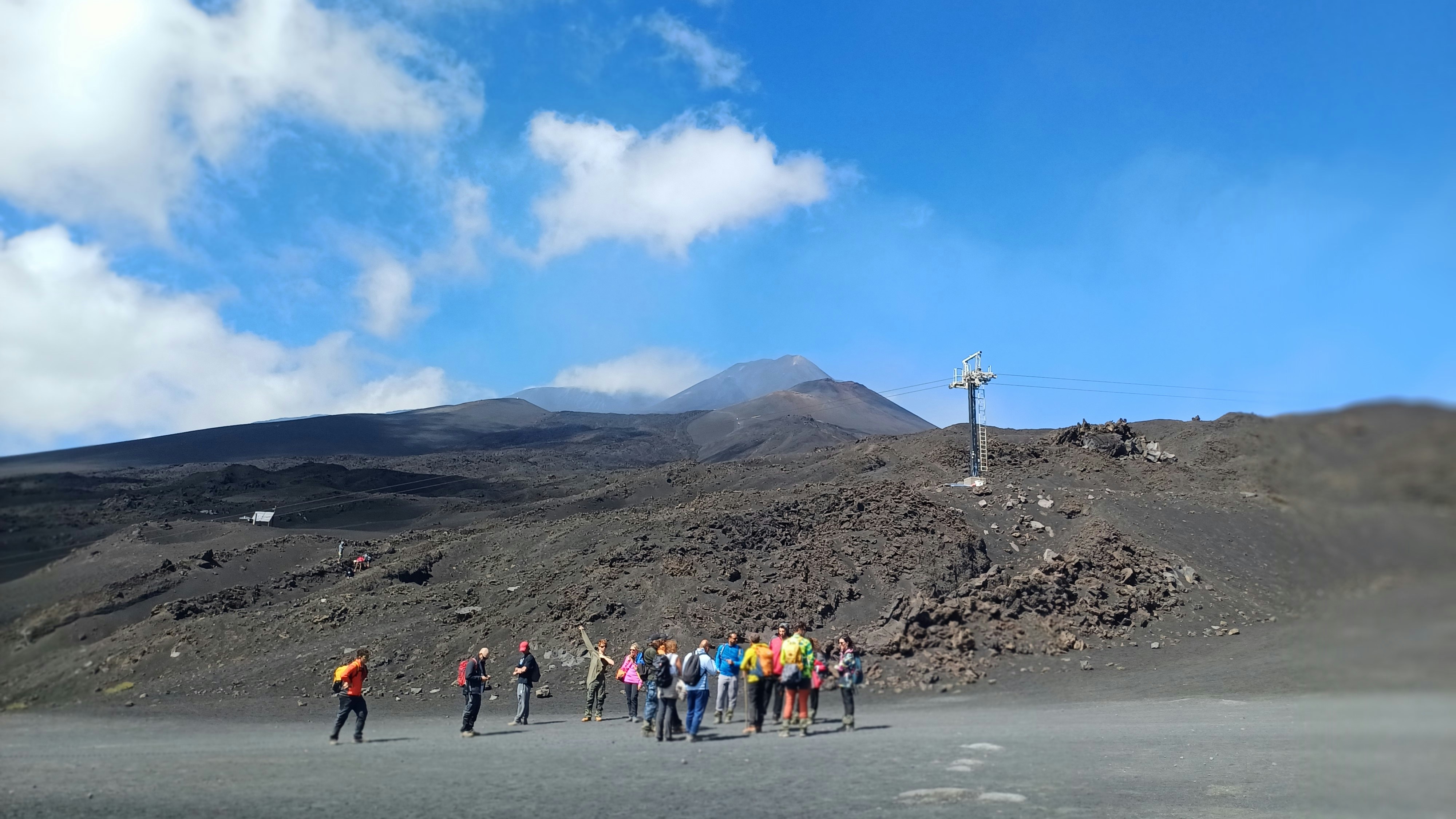 Group of hikers at the base of a smoking volcano