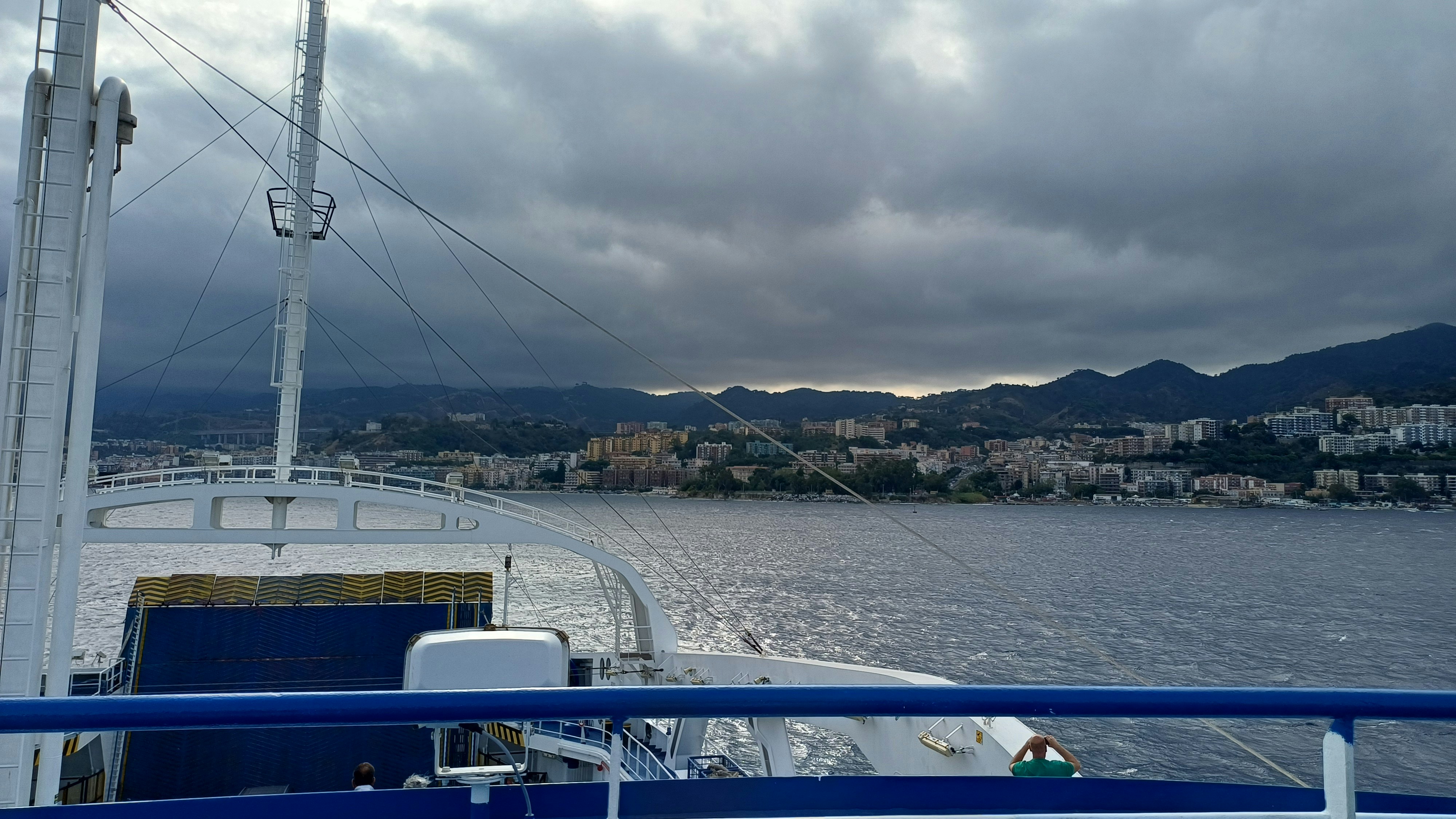 Ferry approaching a coastal city under cloudy skies
