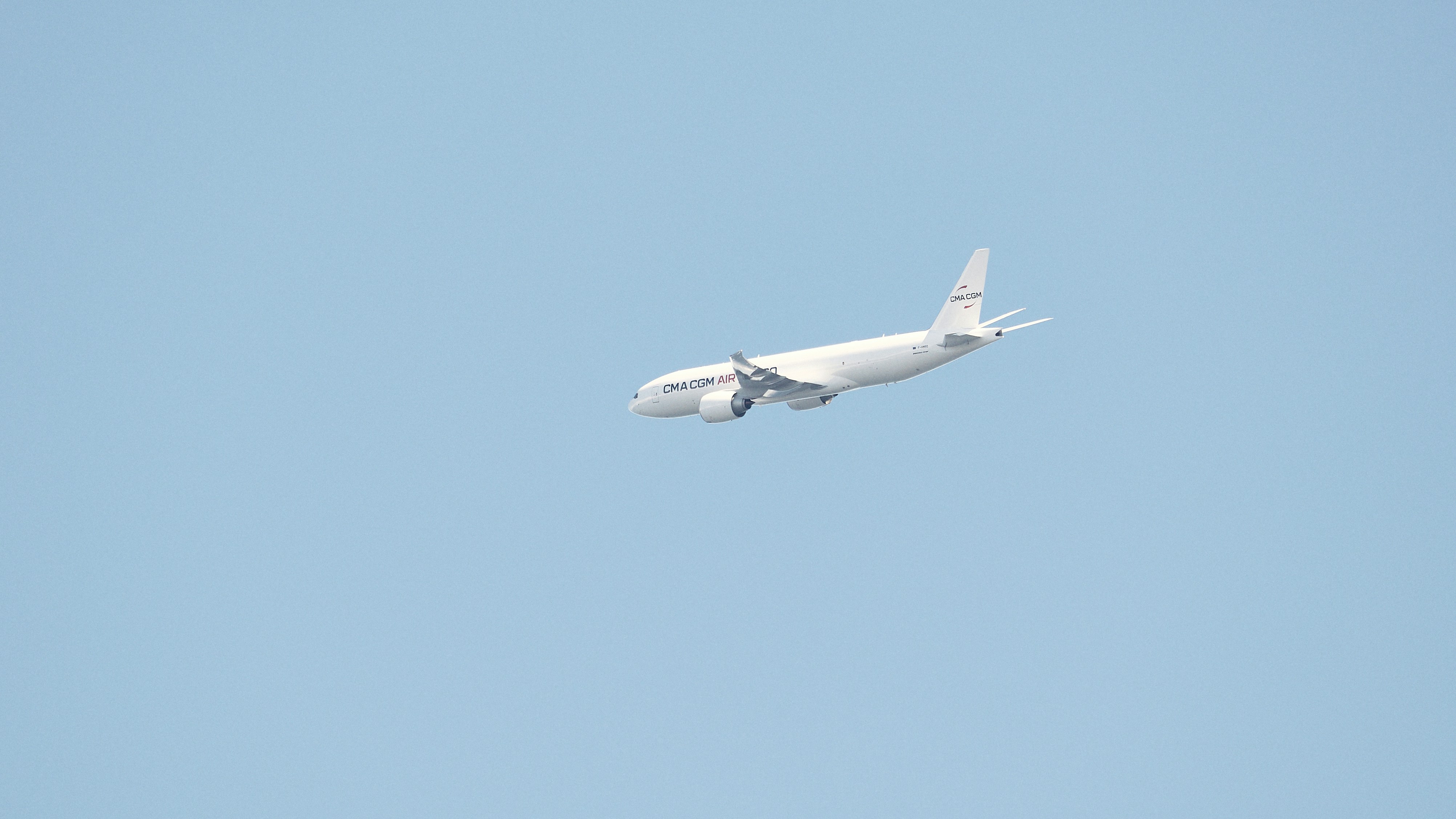 A white airplane flying in a clear blue sky.