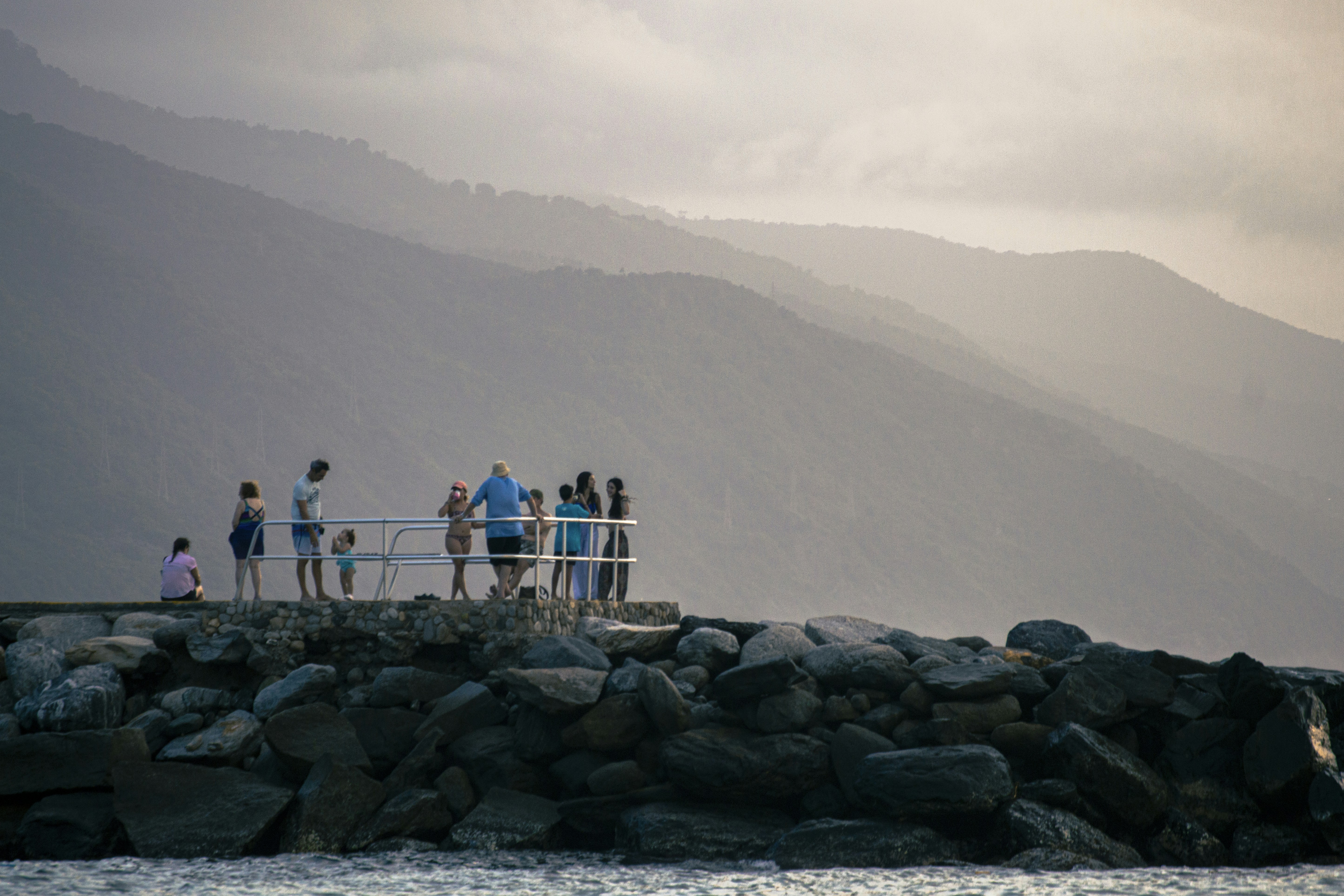 Evening Assembly on a Granite Breakwater Beneath Misty Coastal Ridges