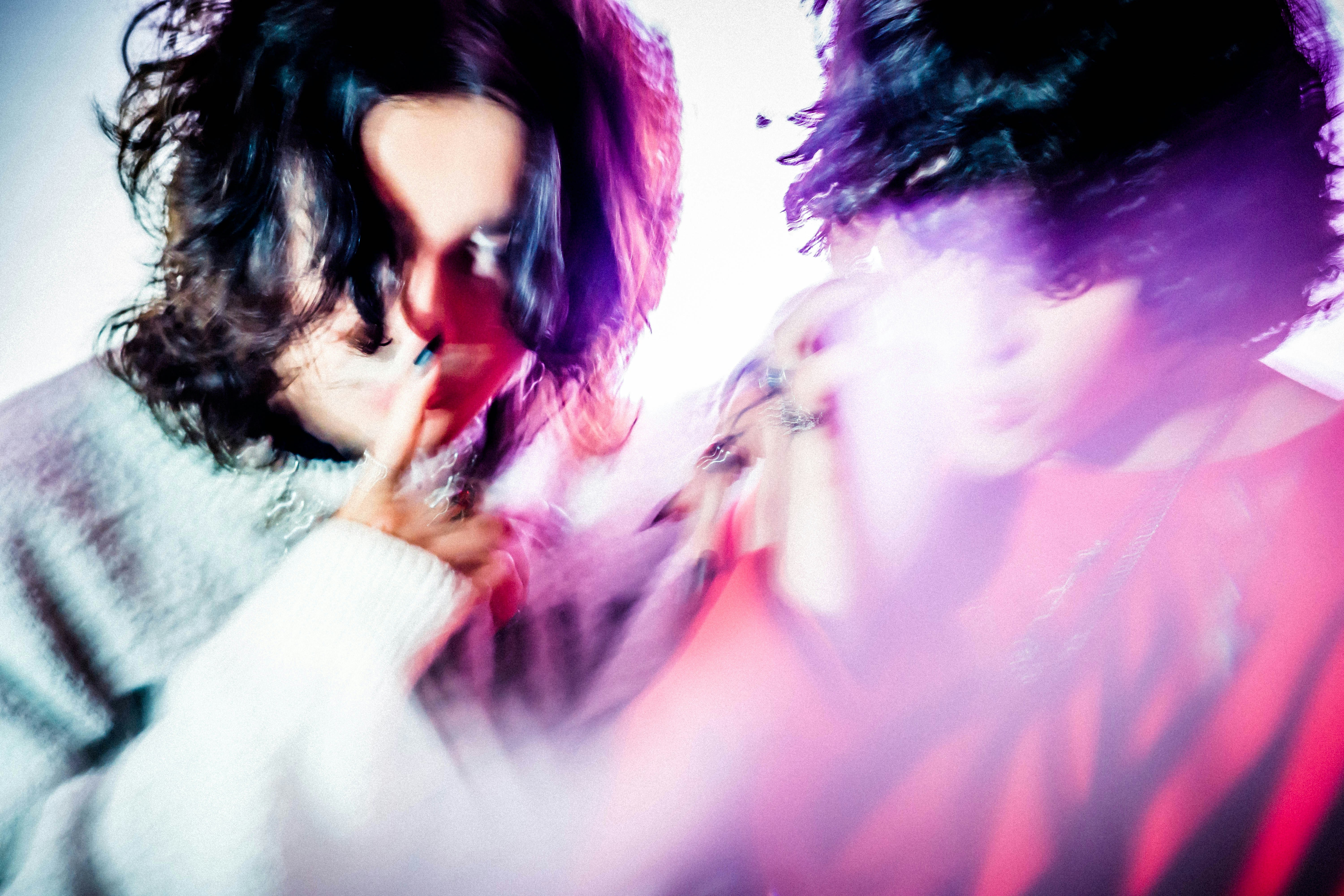 Two figures in a dynamic pose, embodying a moment of connection and secrecy, with vibrant colors and ethereal lighting effects.