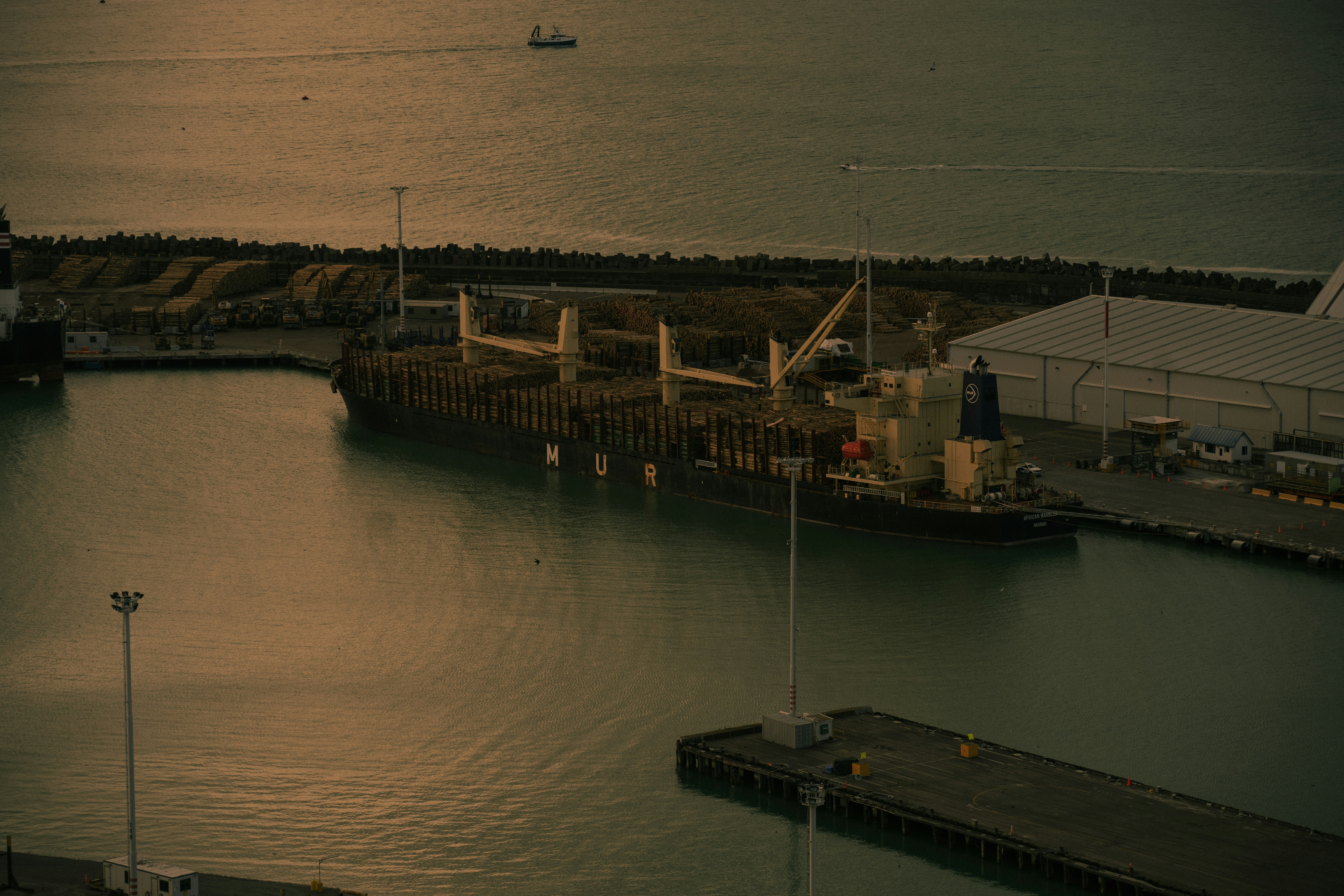 Cargo ship docked in a harbor at dawn.