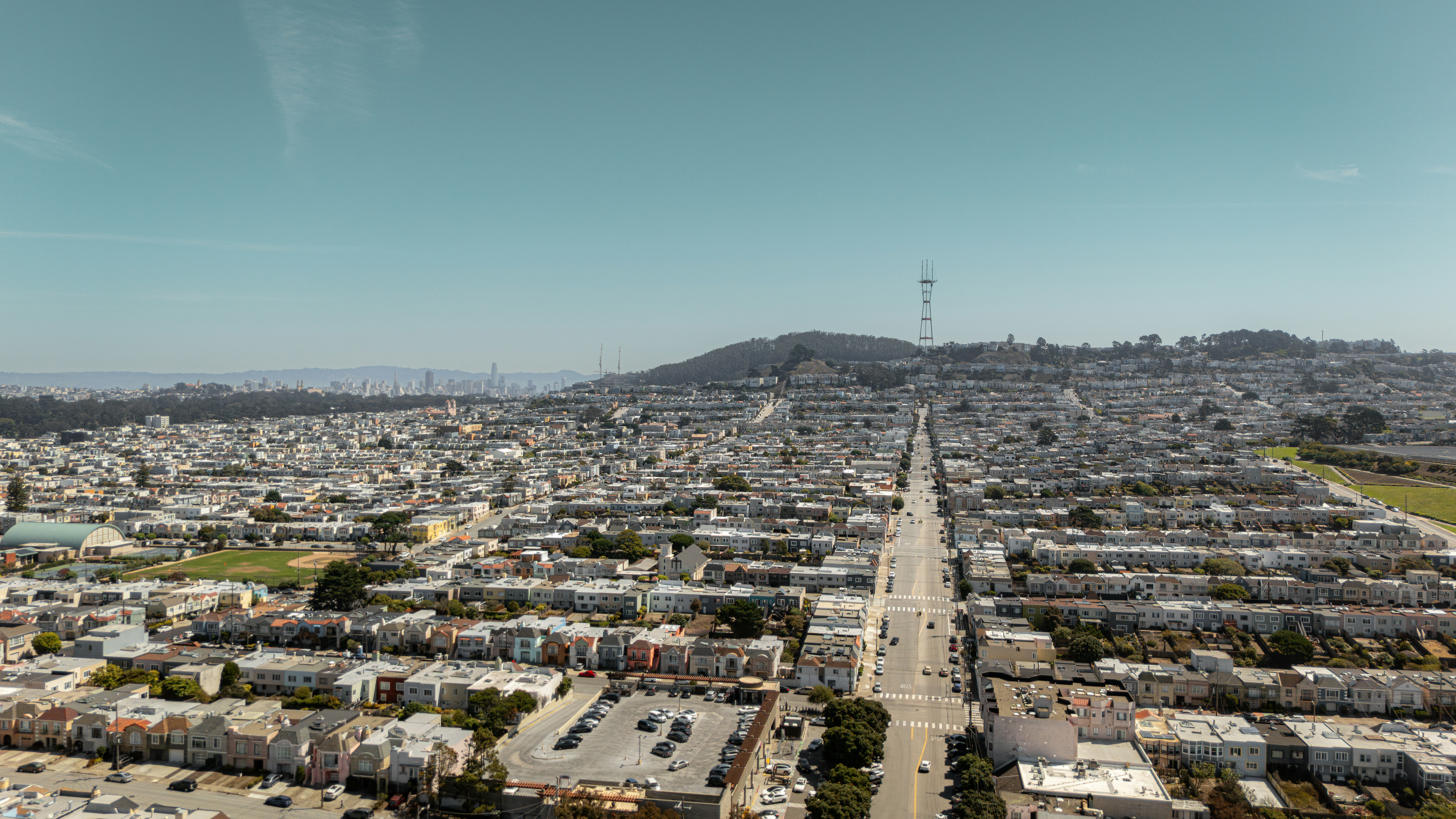 Aerial view showcasing the intricate layout of city blocks, streets, and greenery, highlighting the urban landscape. The scene captures a blend of residential and commercial areas.