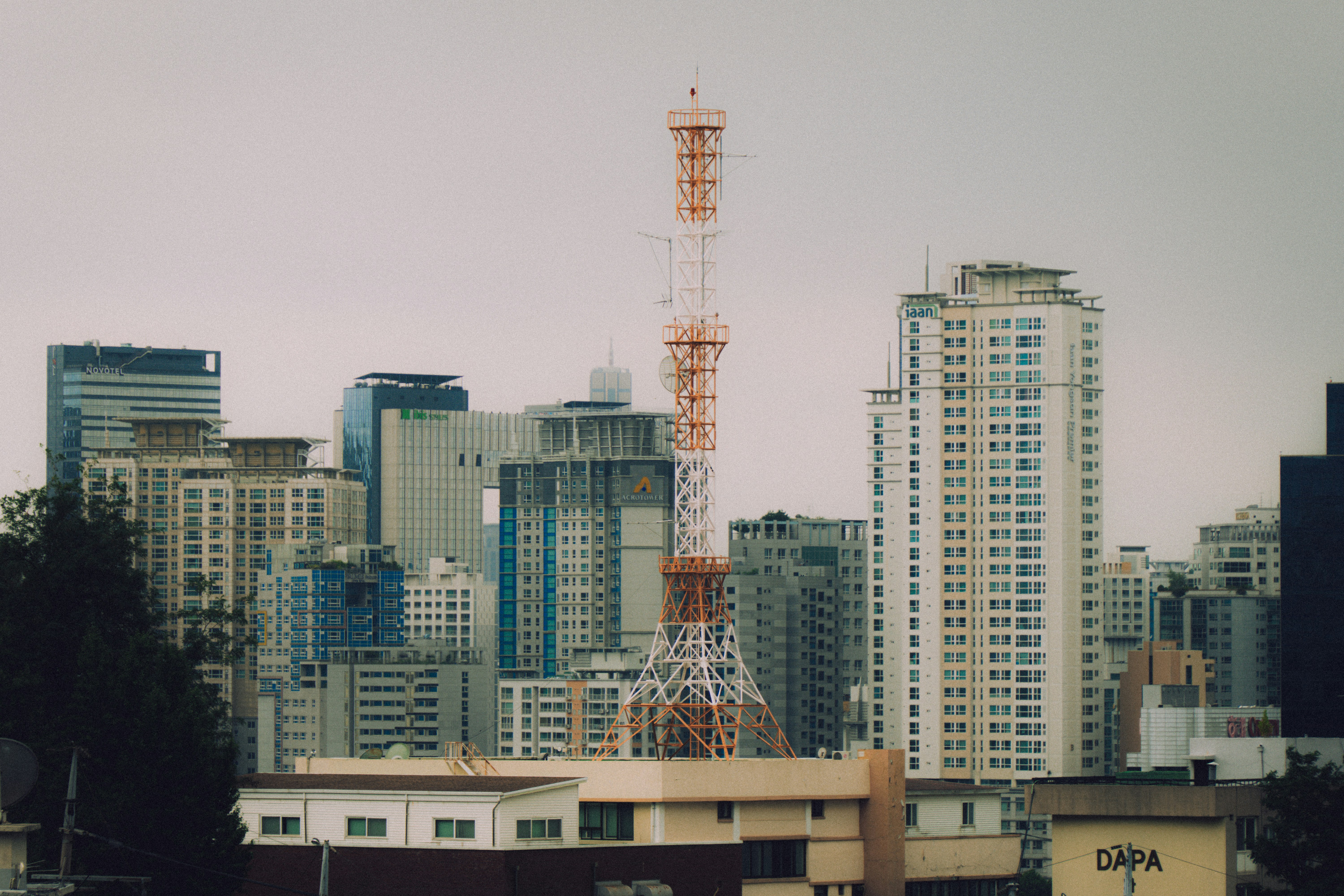 Tall communication tower stands amidst modern city buildings.