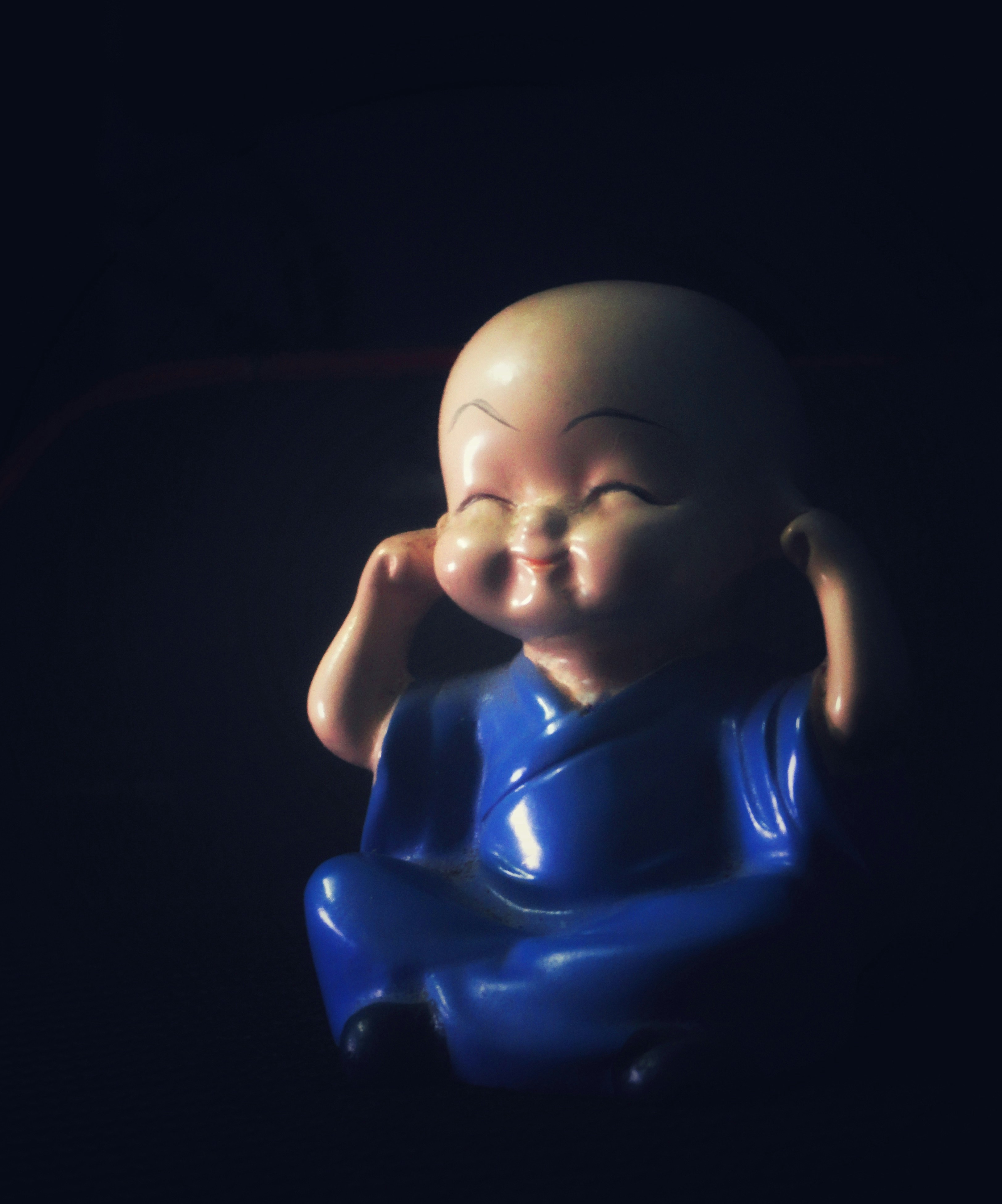 A small statue of a meditating monk in blue robes.