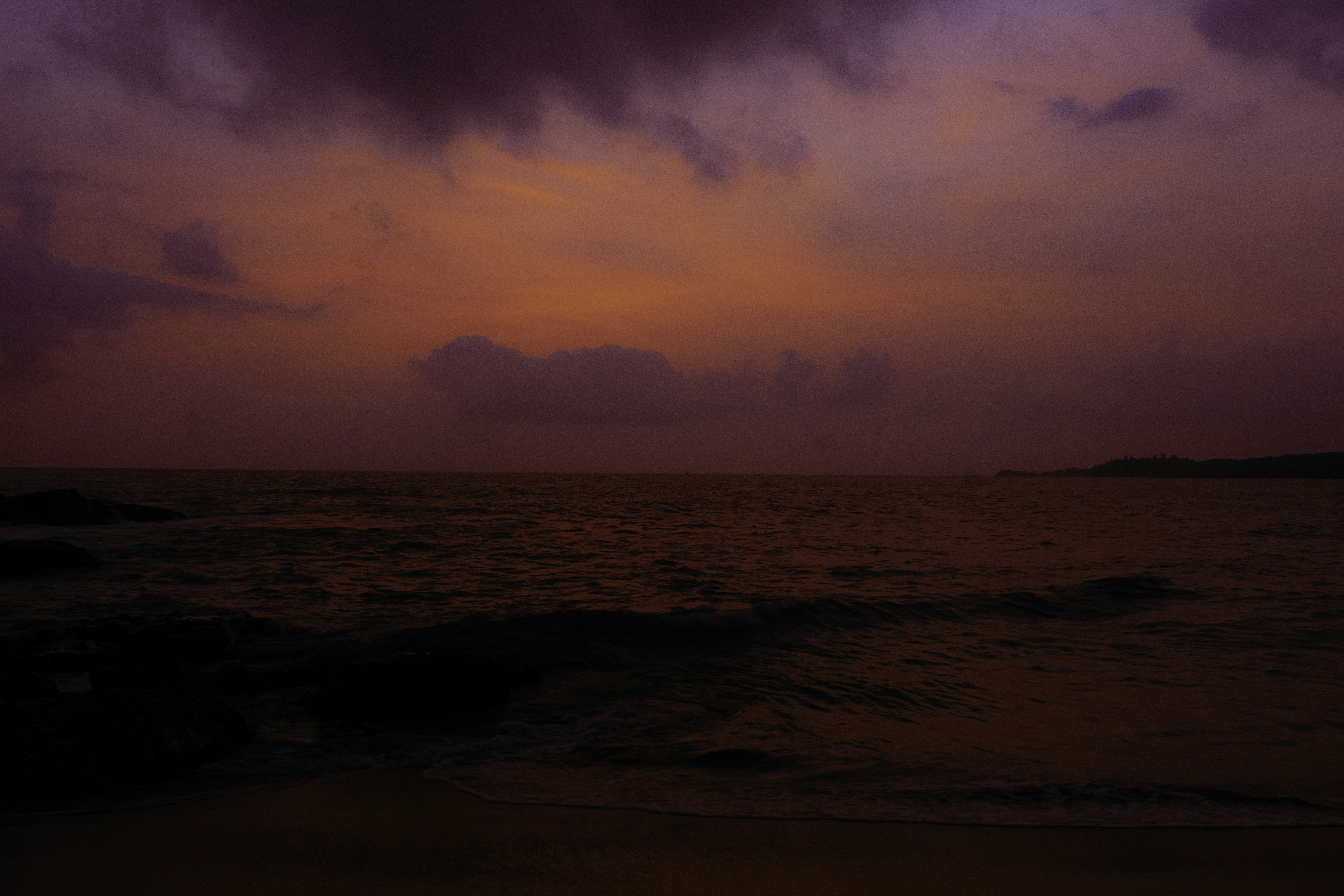A breathtaking twilight over Sinquerim Beach, where the deep hues of the sky meet the calm Arabian Sea, creating a tranquil and captivating evening scene. | Dramatic sunset over a dark ocean