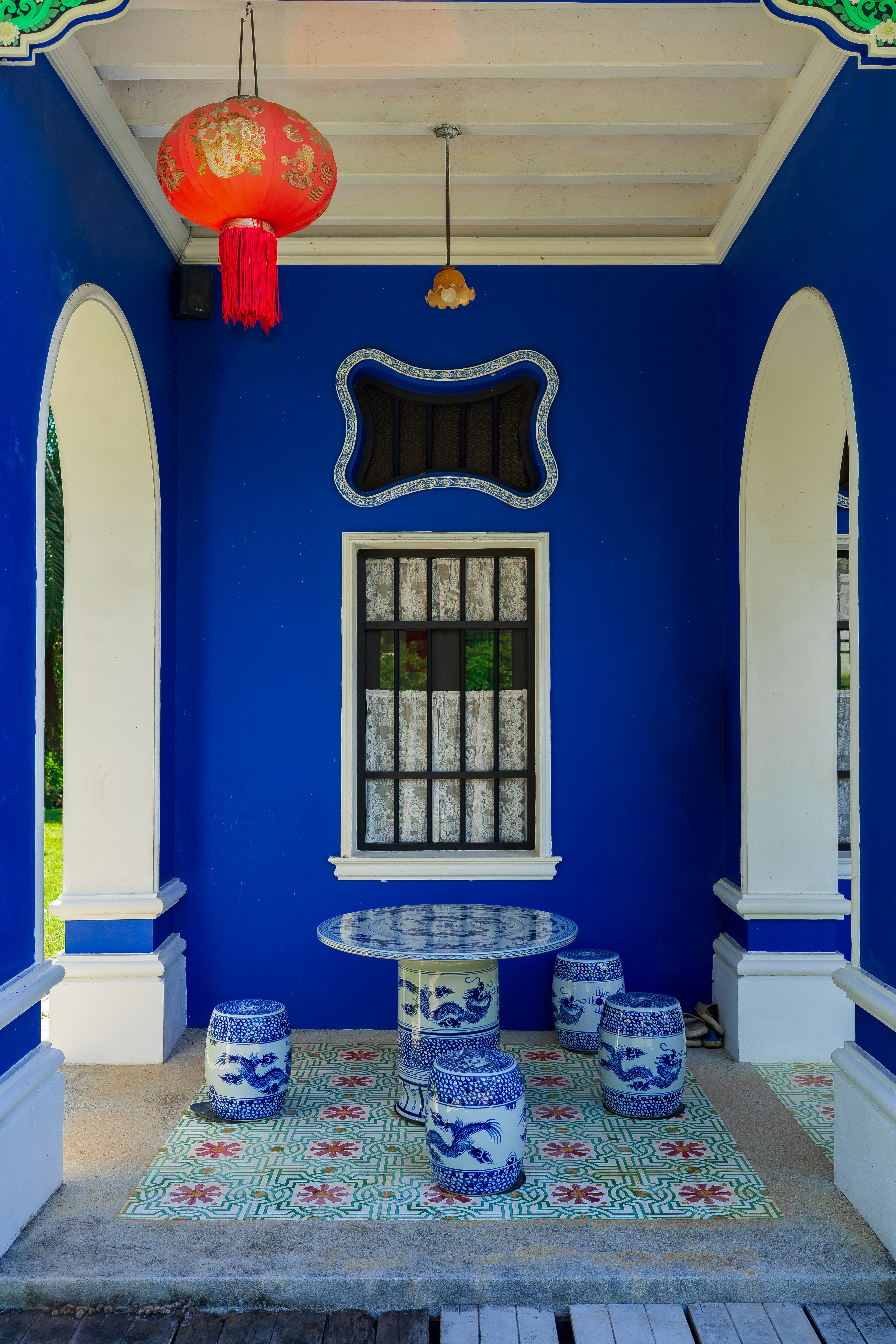 Cerulean Courtyard: White Arches, Circular Window, and a Ring of Porcelain Stools