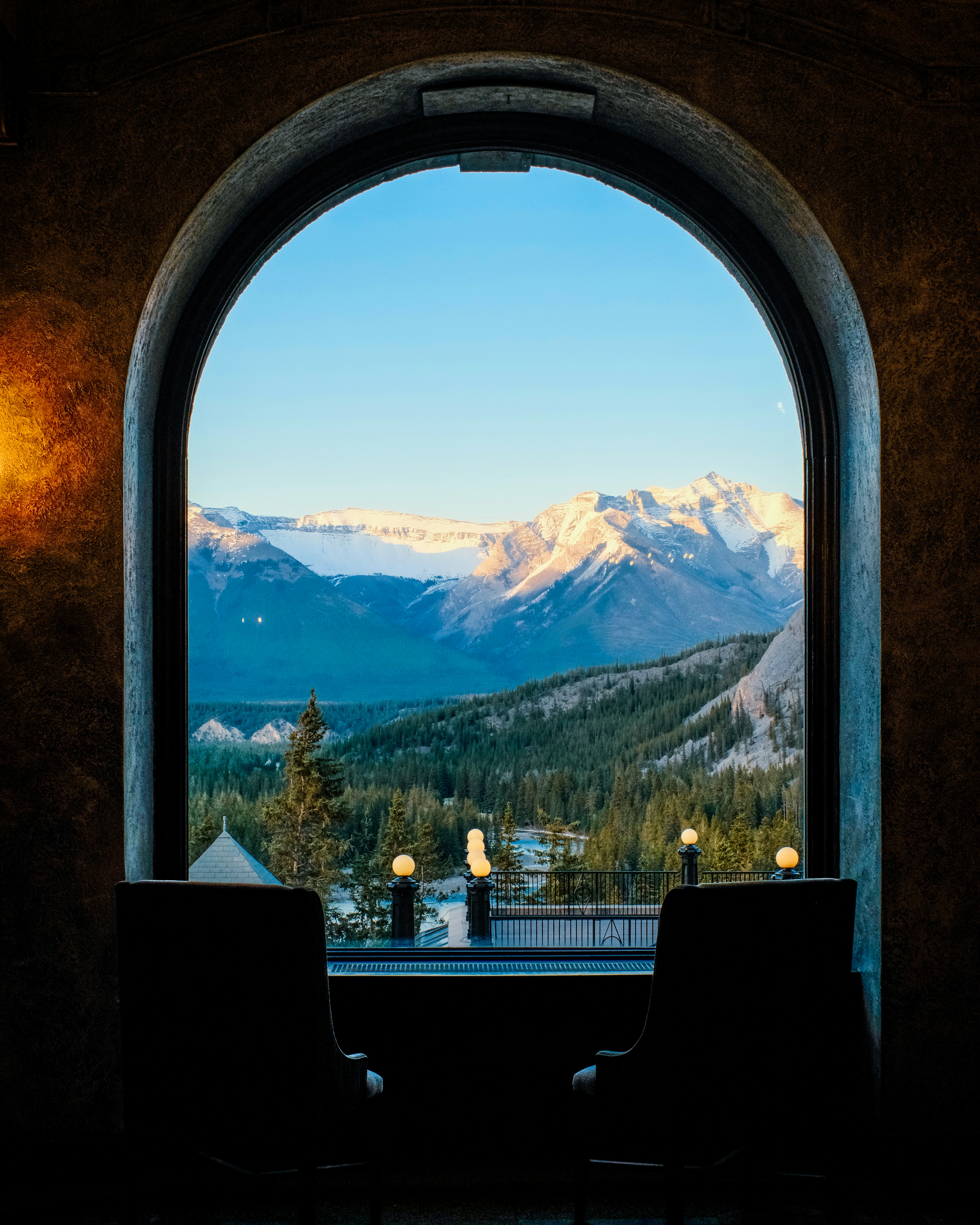 View of the Rockies from a window at the Fairmont Banff Springs. | Snowy mountains seen through an arched window
