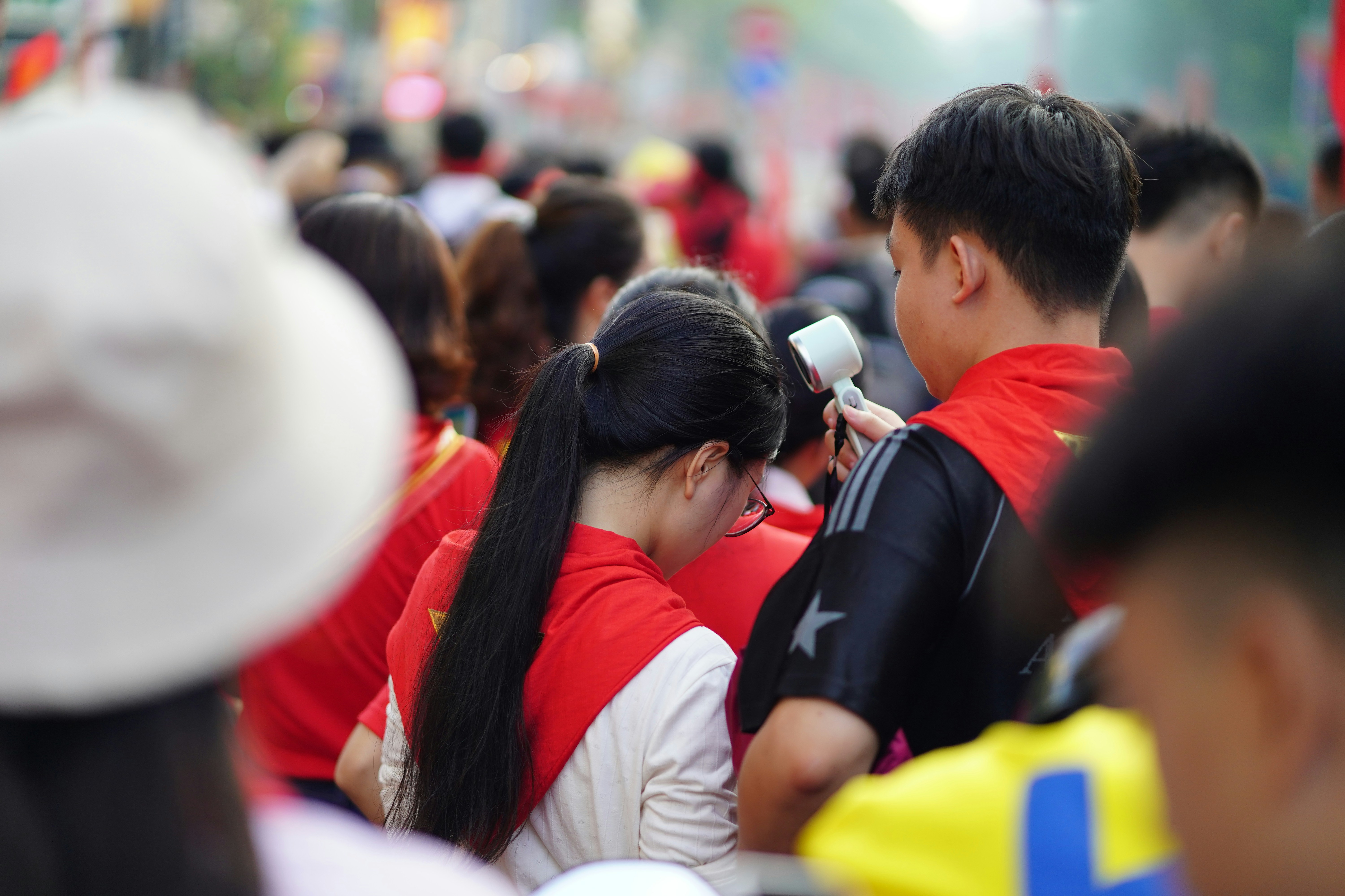 Crowd of people wearing red scarves during a festive event, showcasing a shared sense of community and spirit.