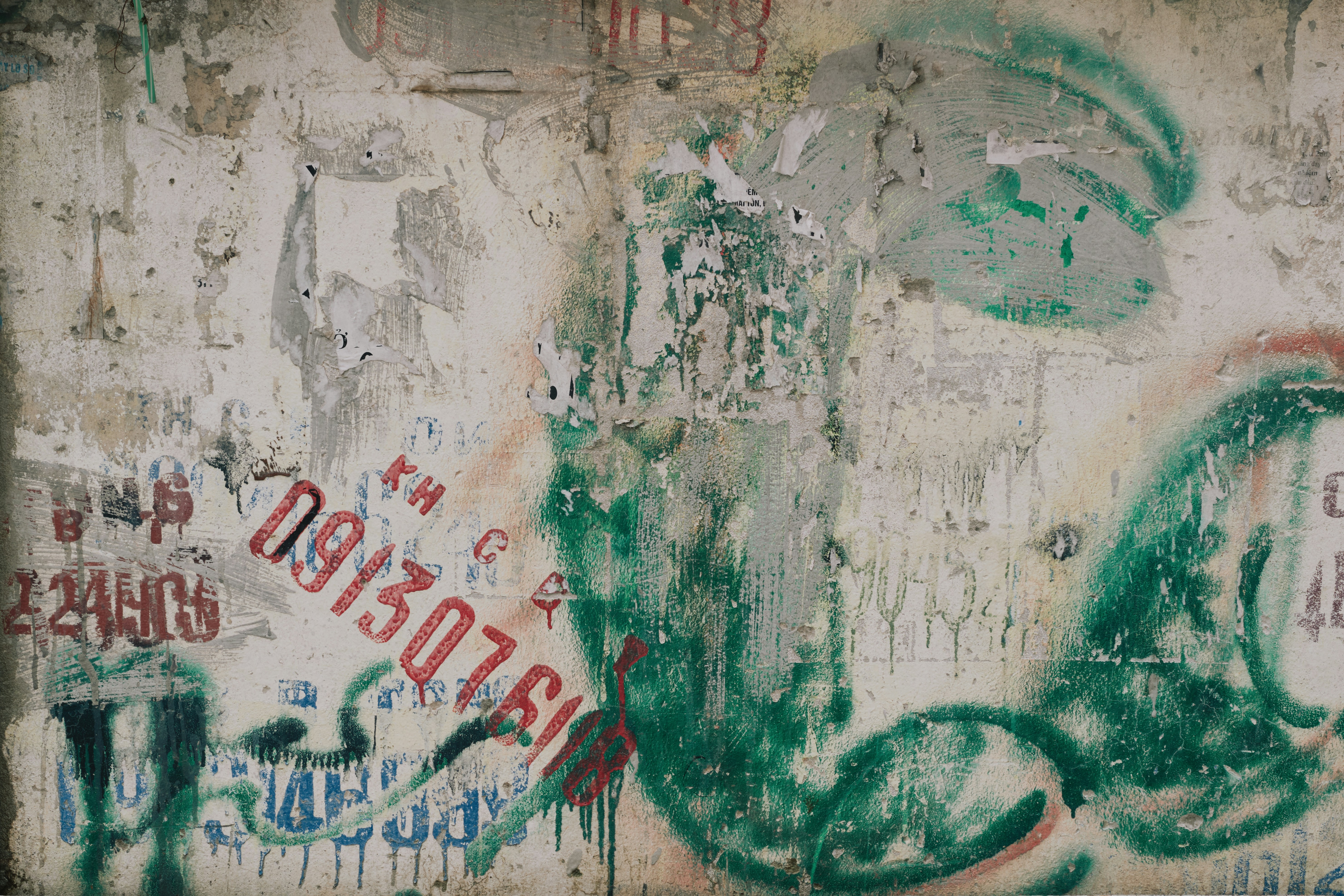 Abstract detail of a weathered wall with faded paint and rough textures, captured in Hanoi, Vietnam. | Graffiti art on a weathered concrete wall