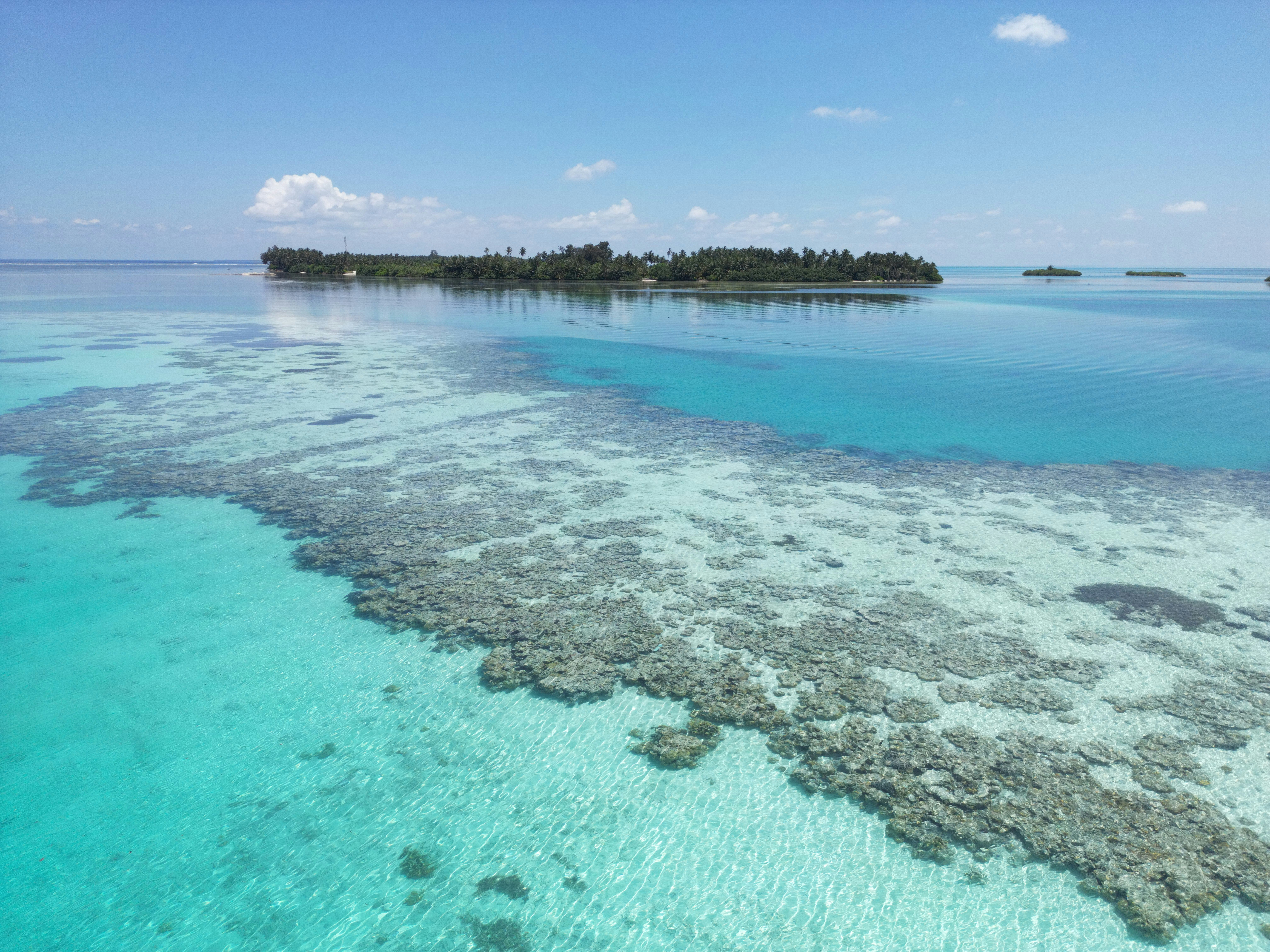 Turquoise ocean water with coral reef and island.