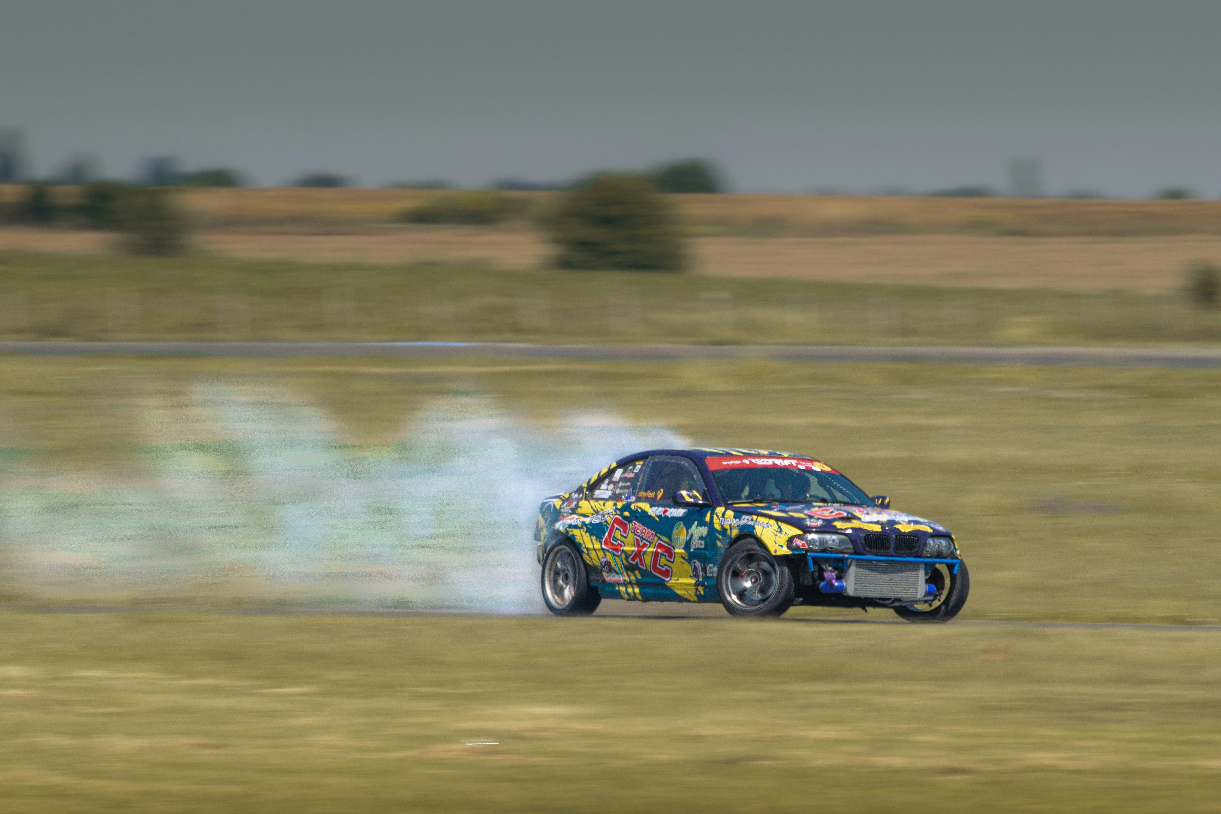 Drifting race car kicking up smoke on a grassy track