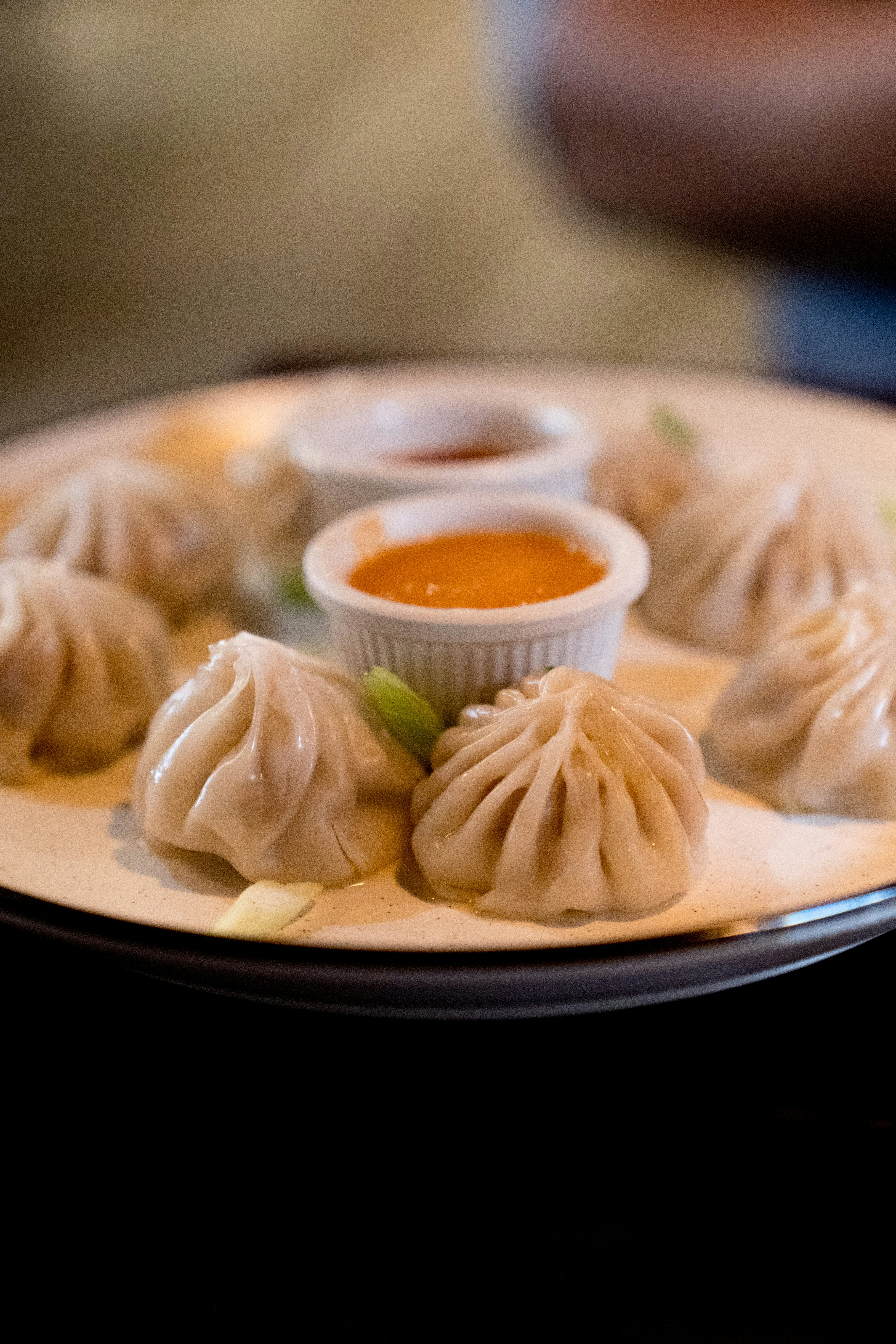 Steamed dumplings served with dipping sauce on a plate.