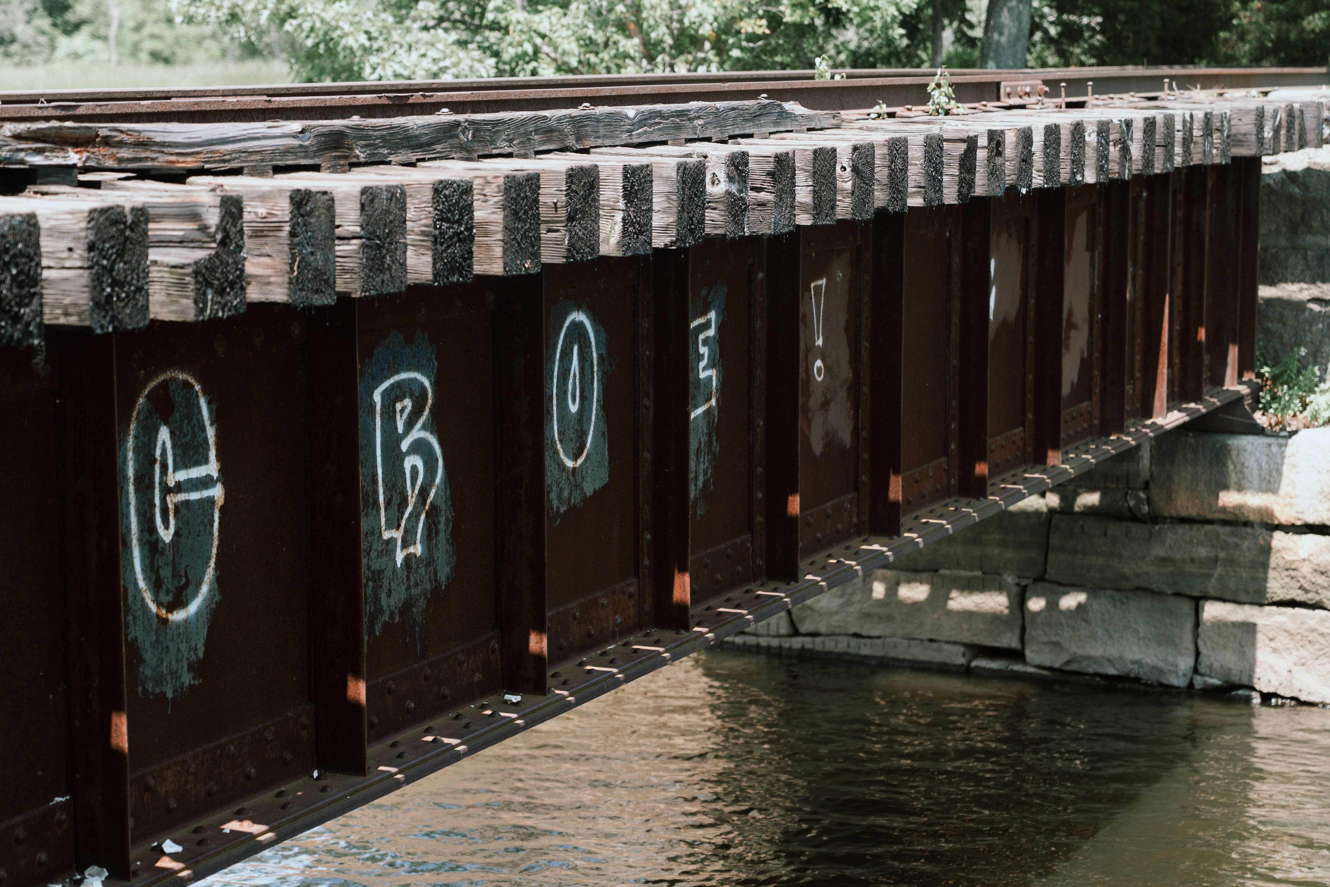 Graffiti on a Rusted Rail Span Over a Quiet Waterway