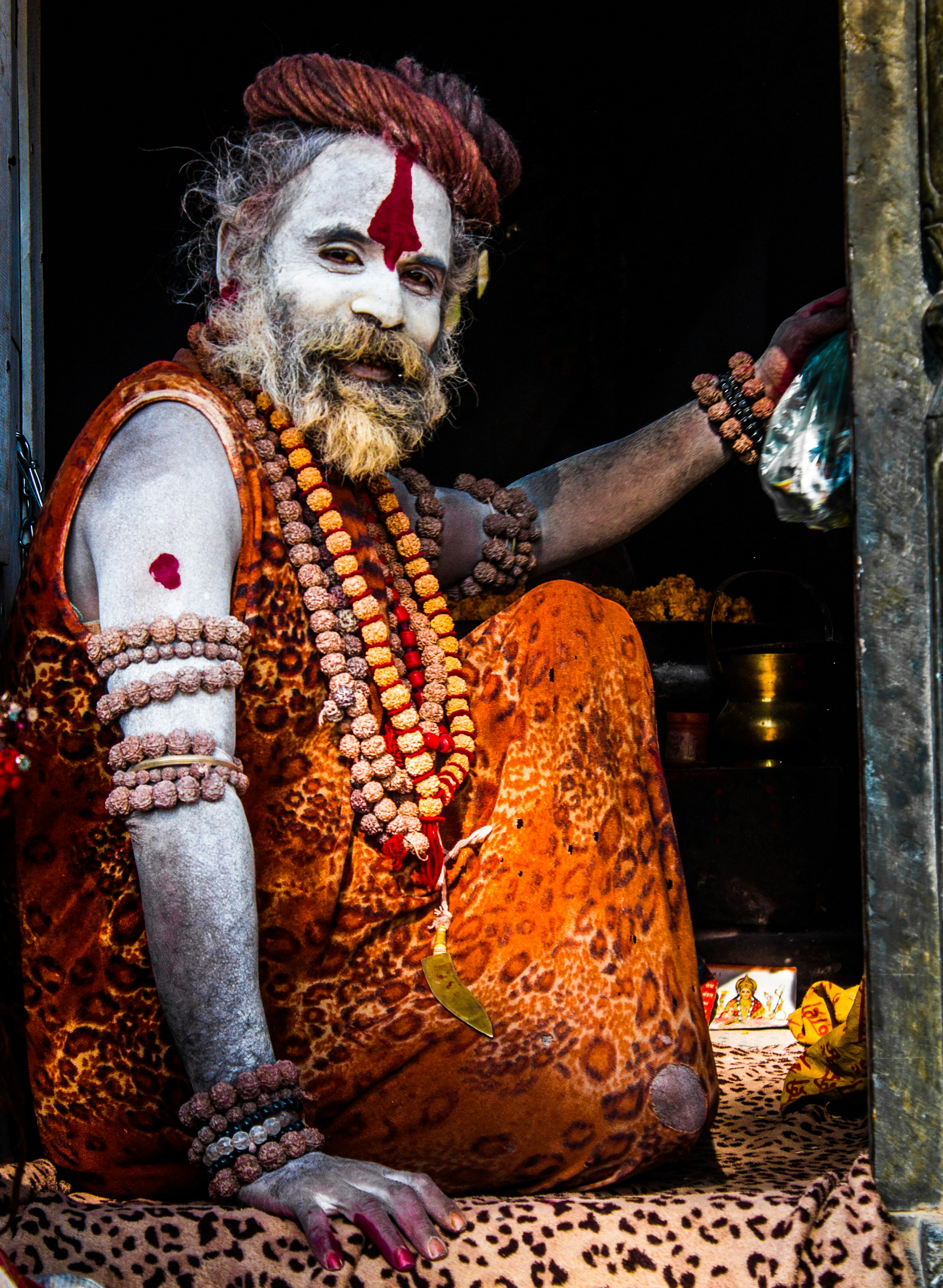 Sadhu in Meditation at Pashupatinath Temple | A sadhu with white body paint and prayer beads sits.