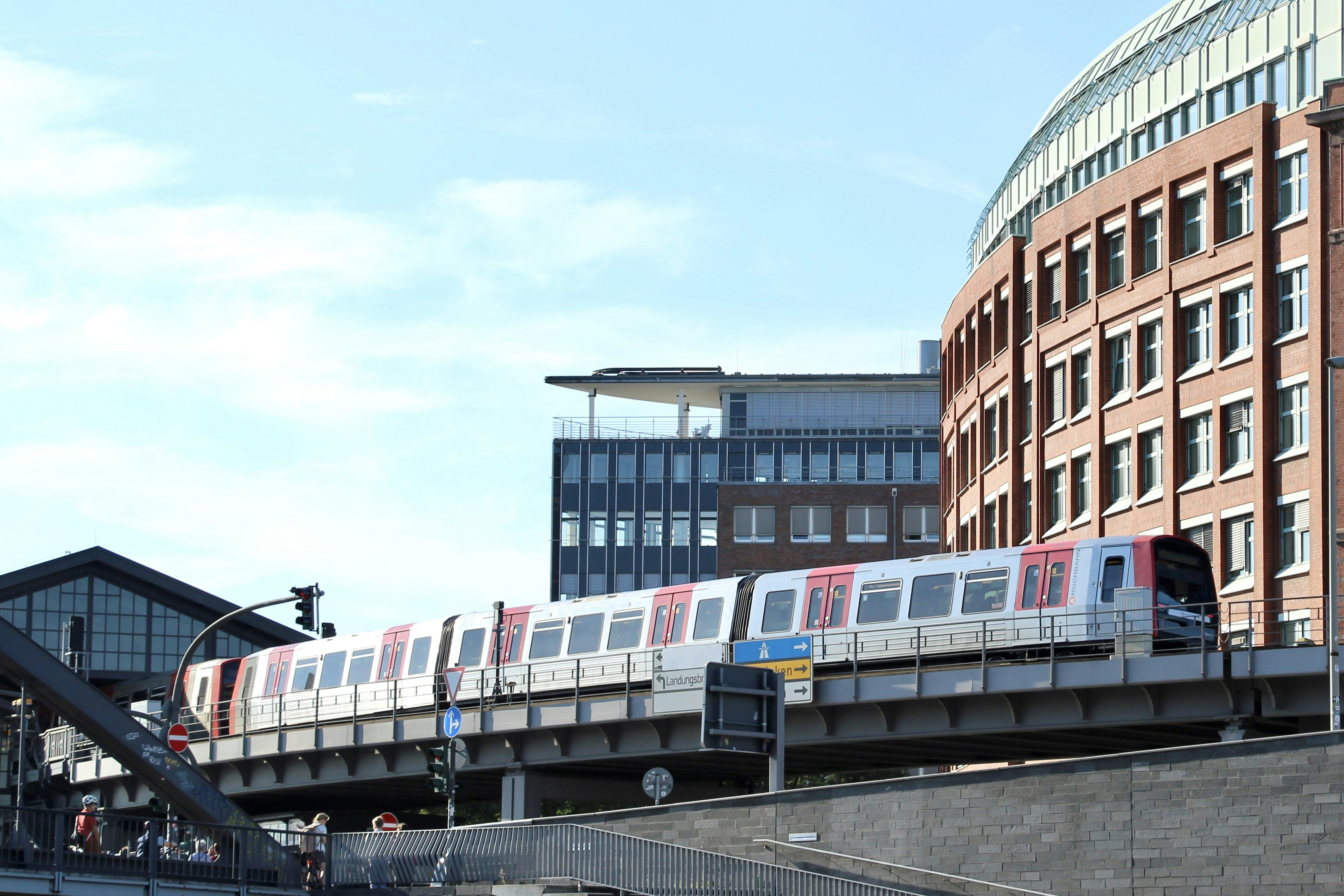 A modern train glides along an elevated track, juxtaposed against contemporary architecture in an urban setting.