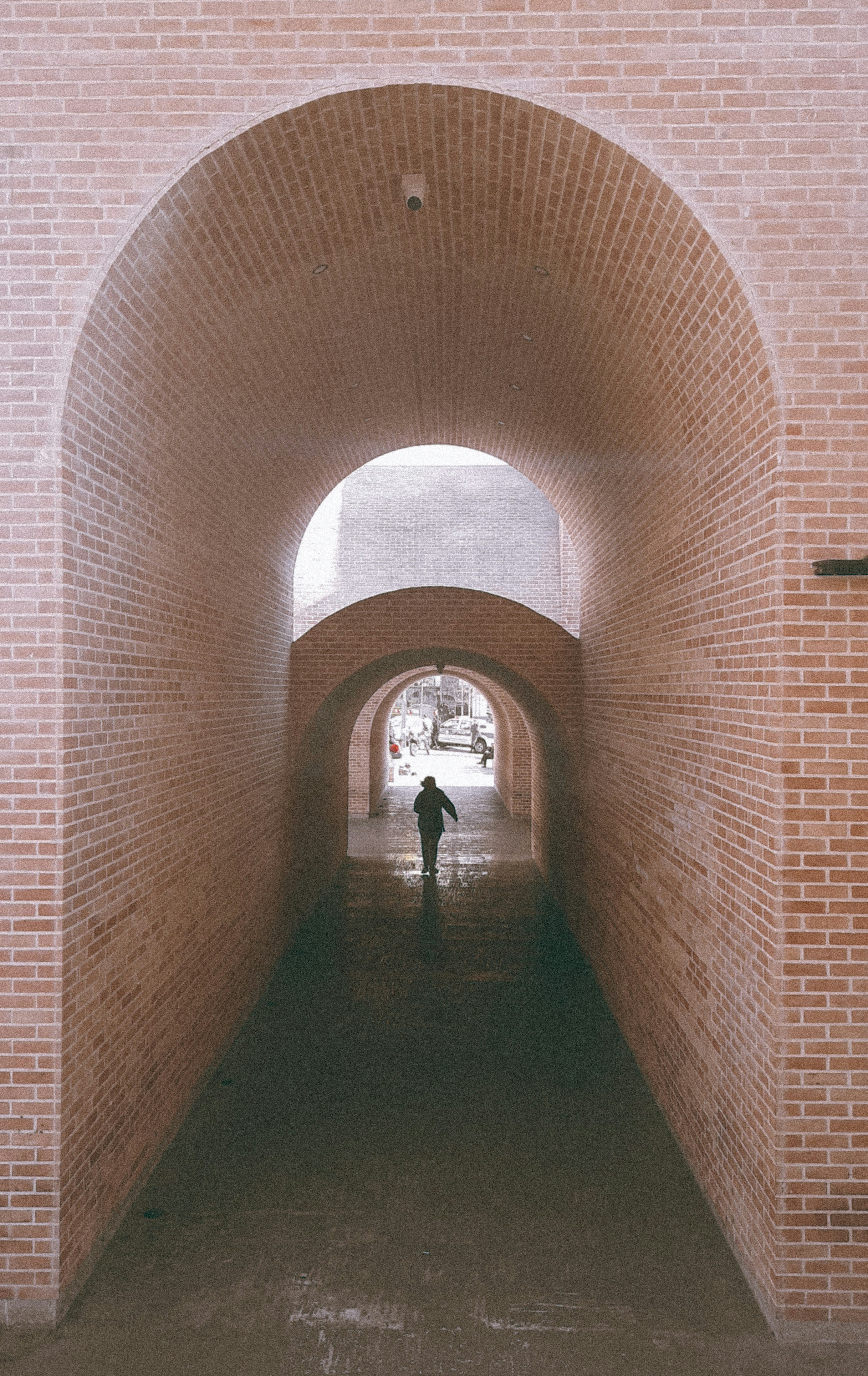 Person walking through arched brick passageway