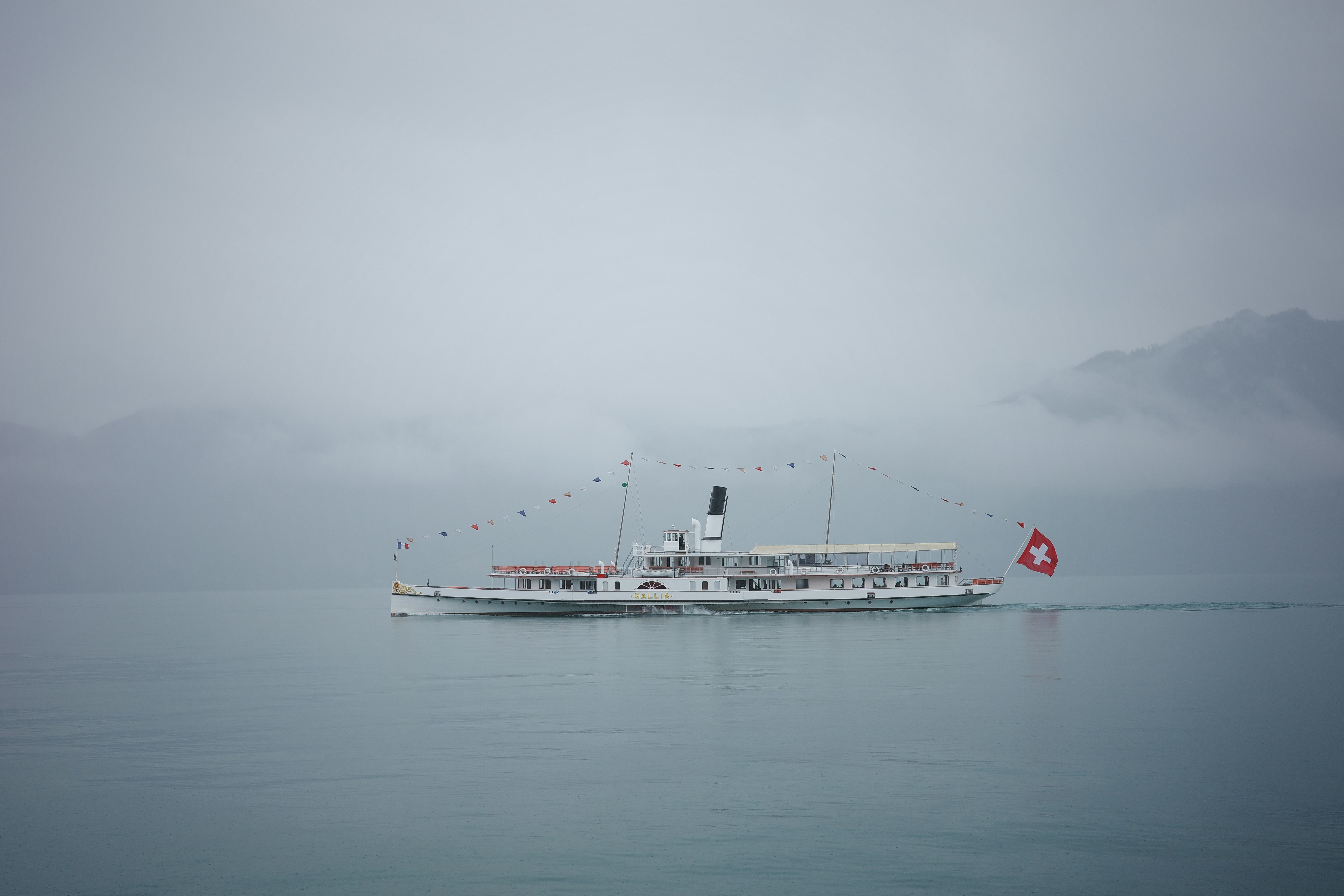 White paddle steamer boat on a misty lake