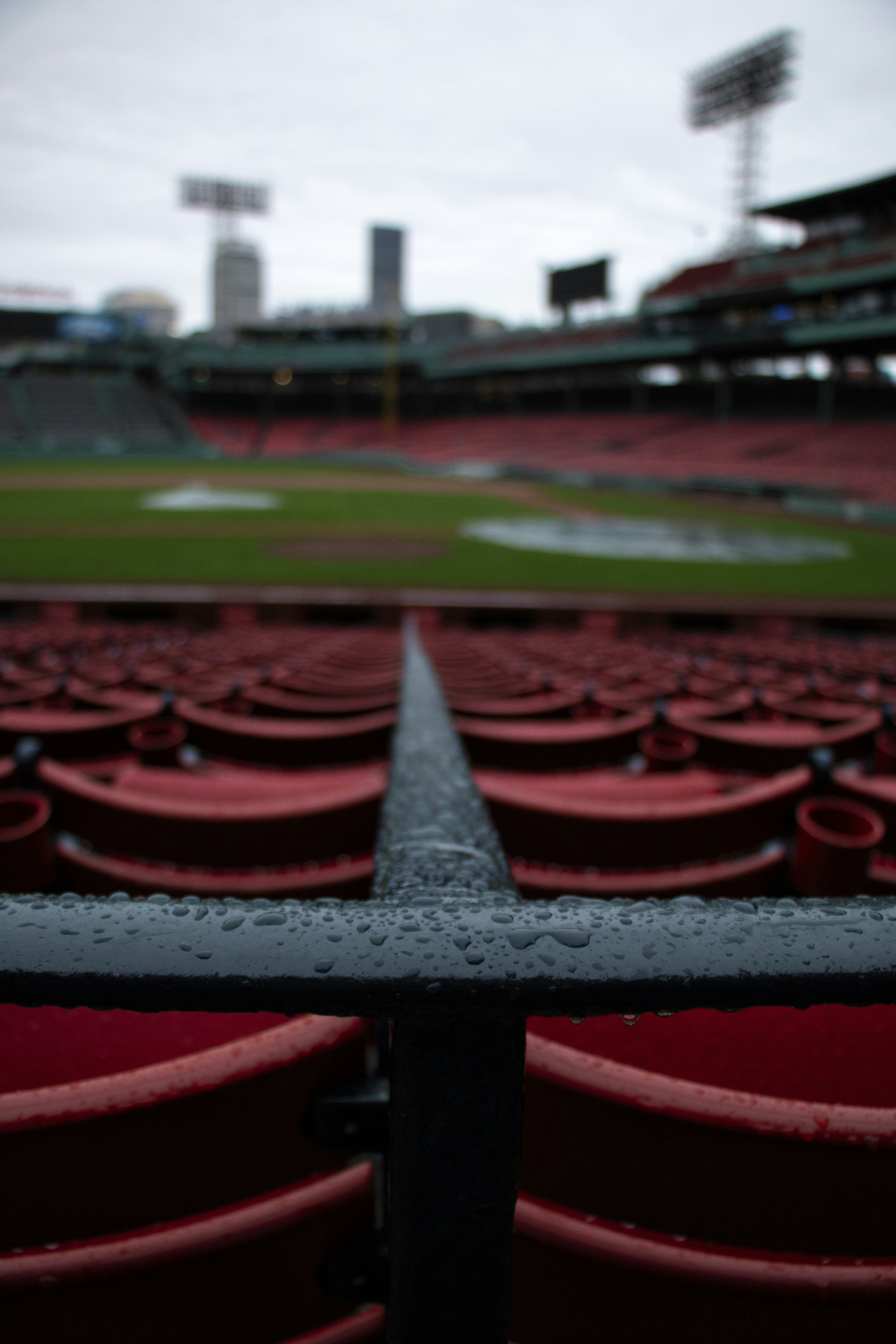 baseball, Fenway, rain, seats, stands, park, Boston | Empty red stadium seats with a baseball field beyond.
