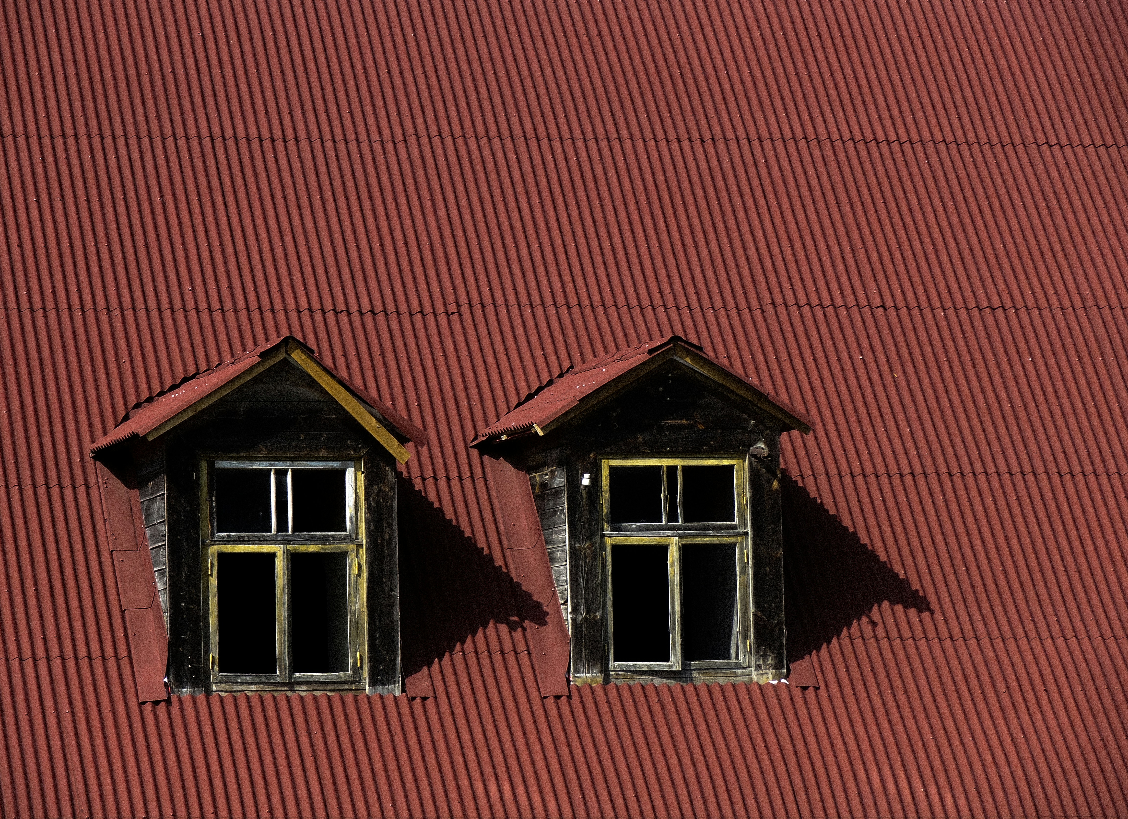 Two dormer windows on a red corrugated roof.