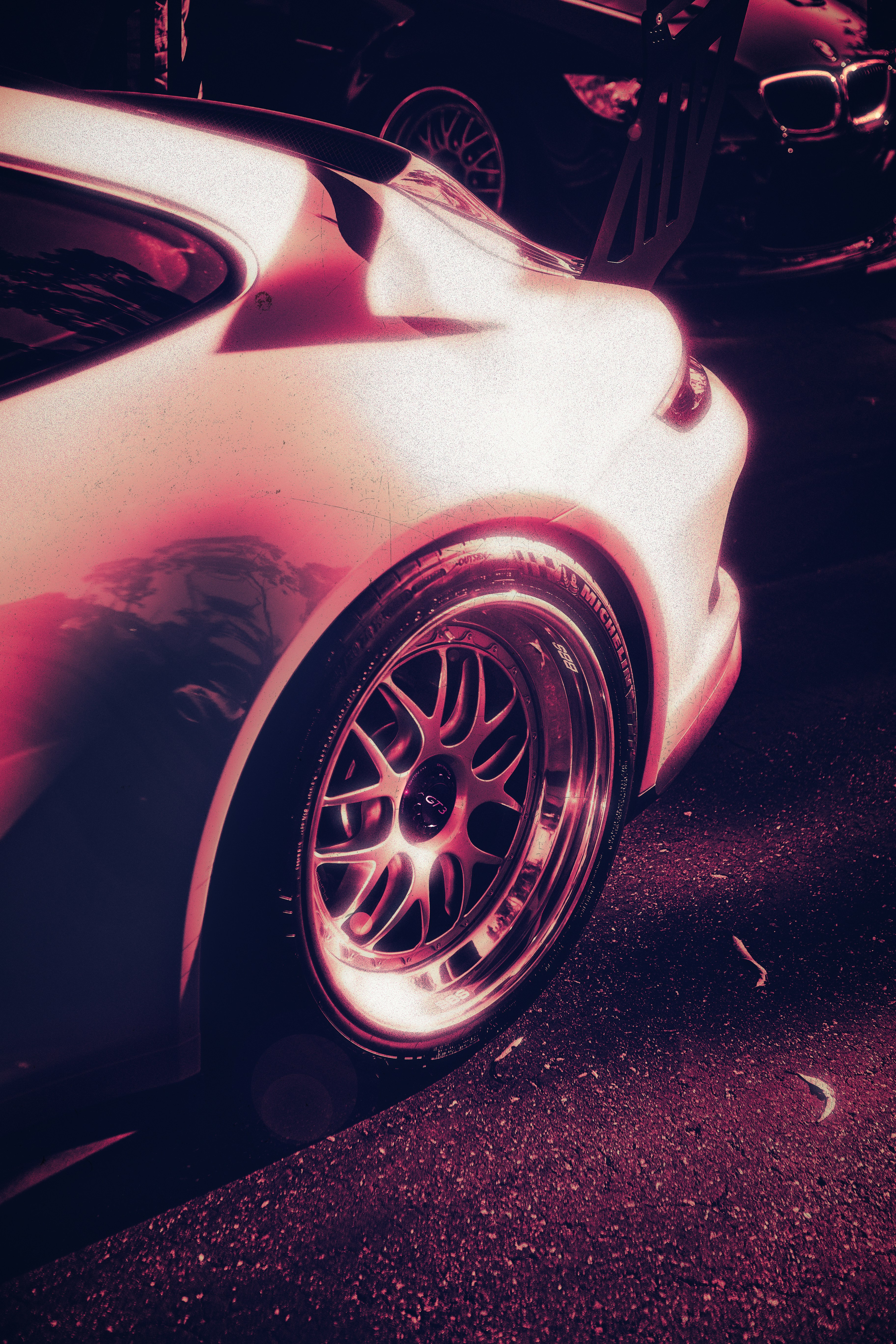 Close-up of a shiny car wheel with a red tint.