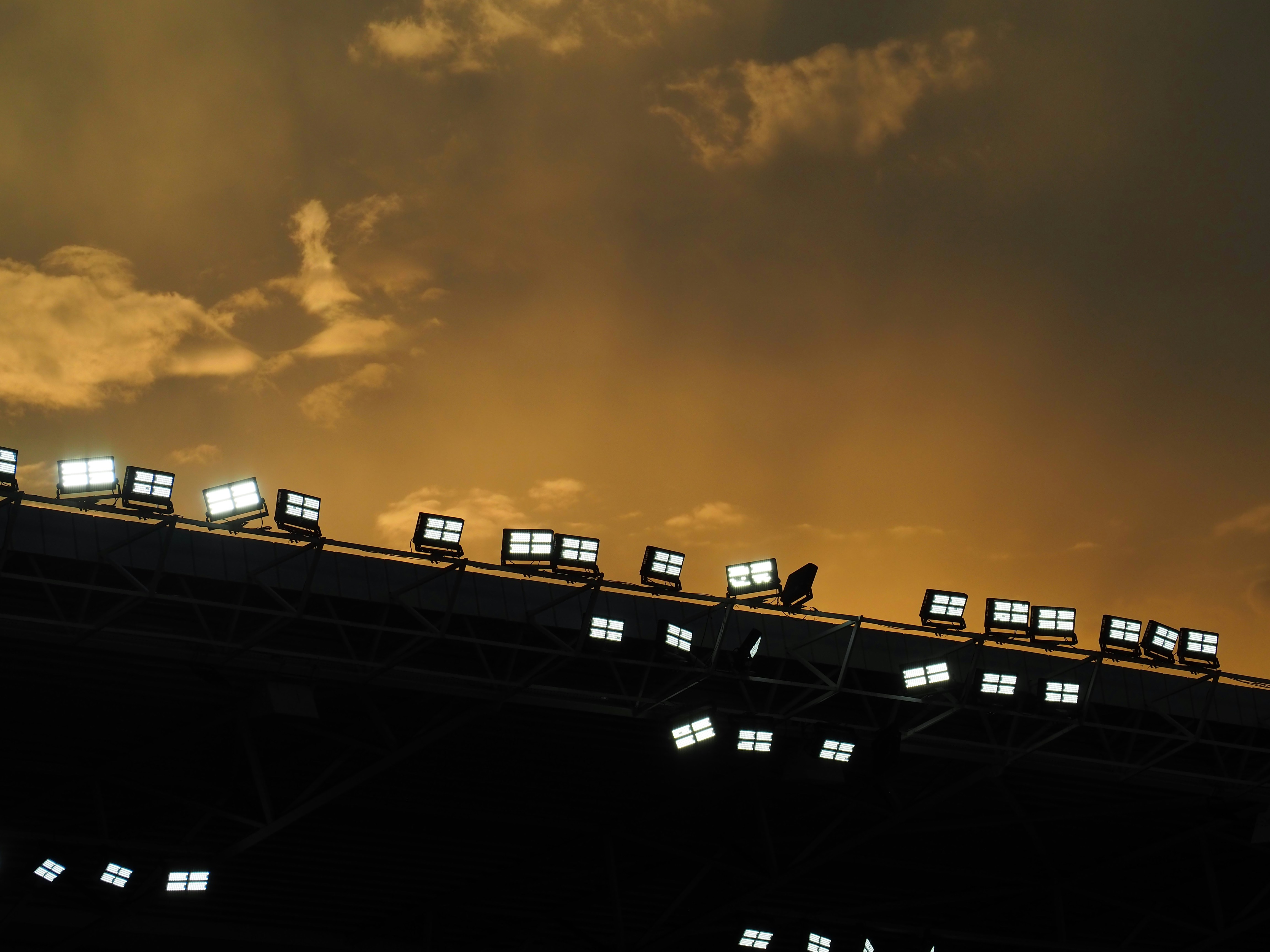 Stadium lights against a dramatic sunset sky