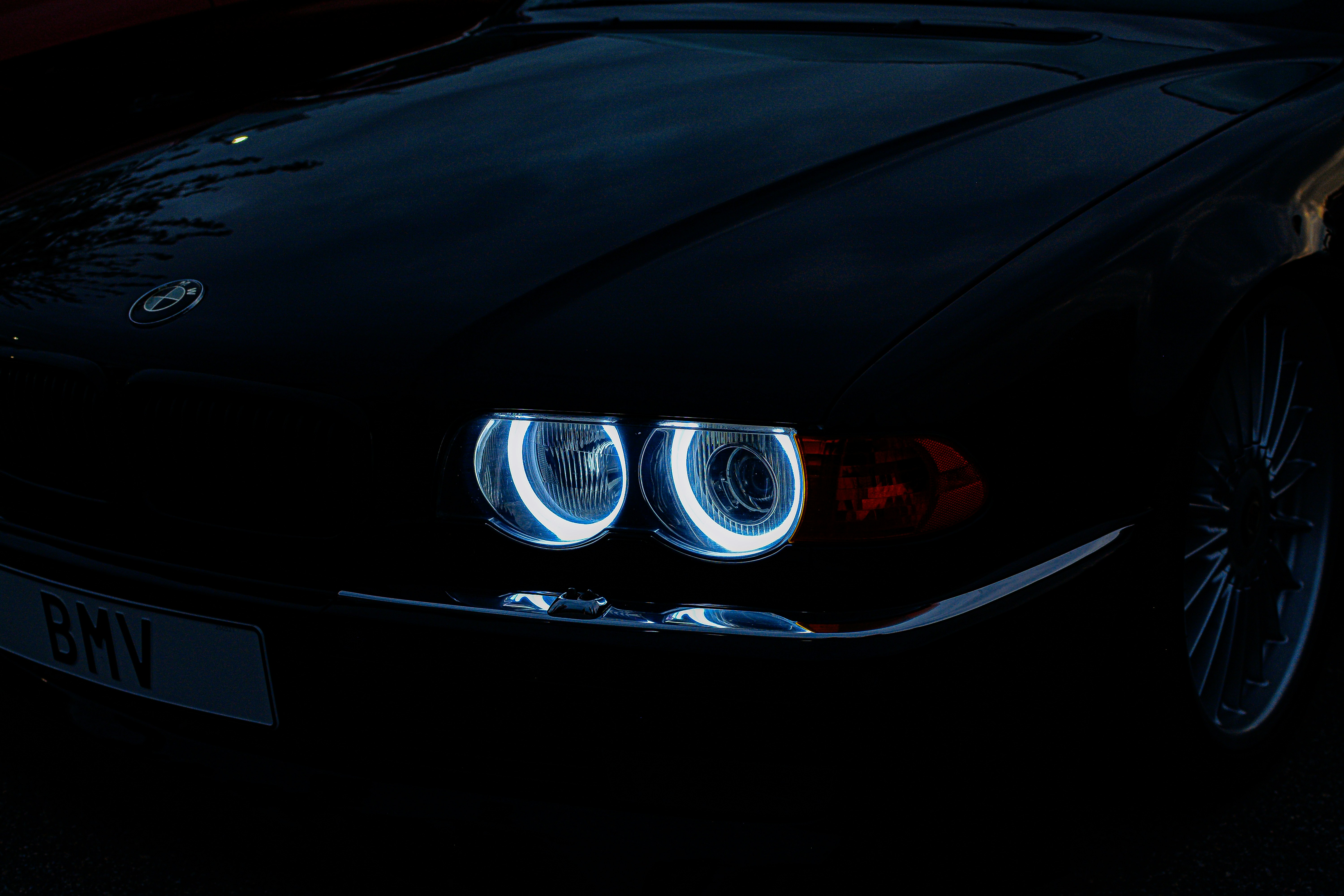 Close-up of a black BMW car headlights at night