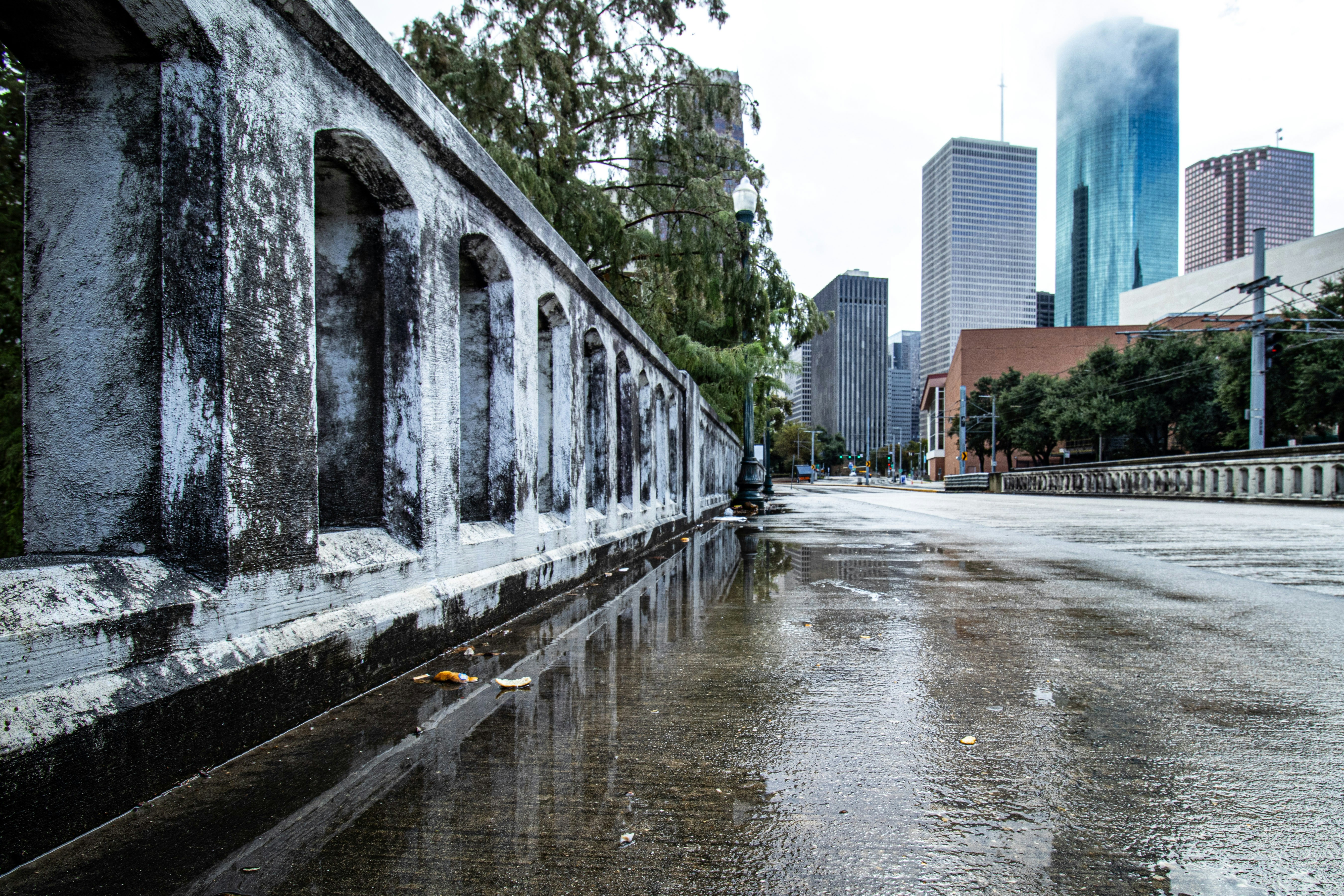 Wet city street with buildings and concrete railing