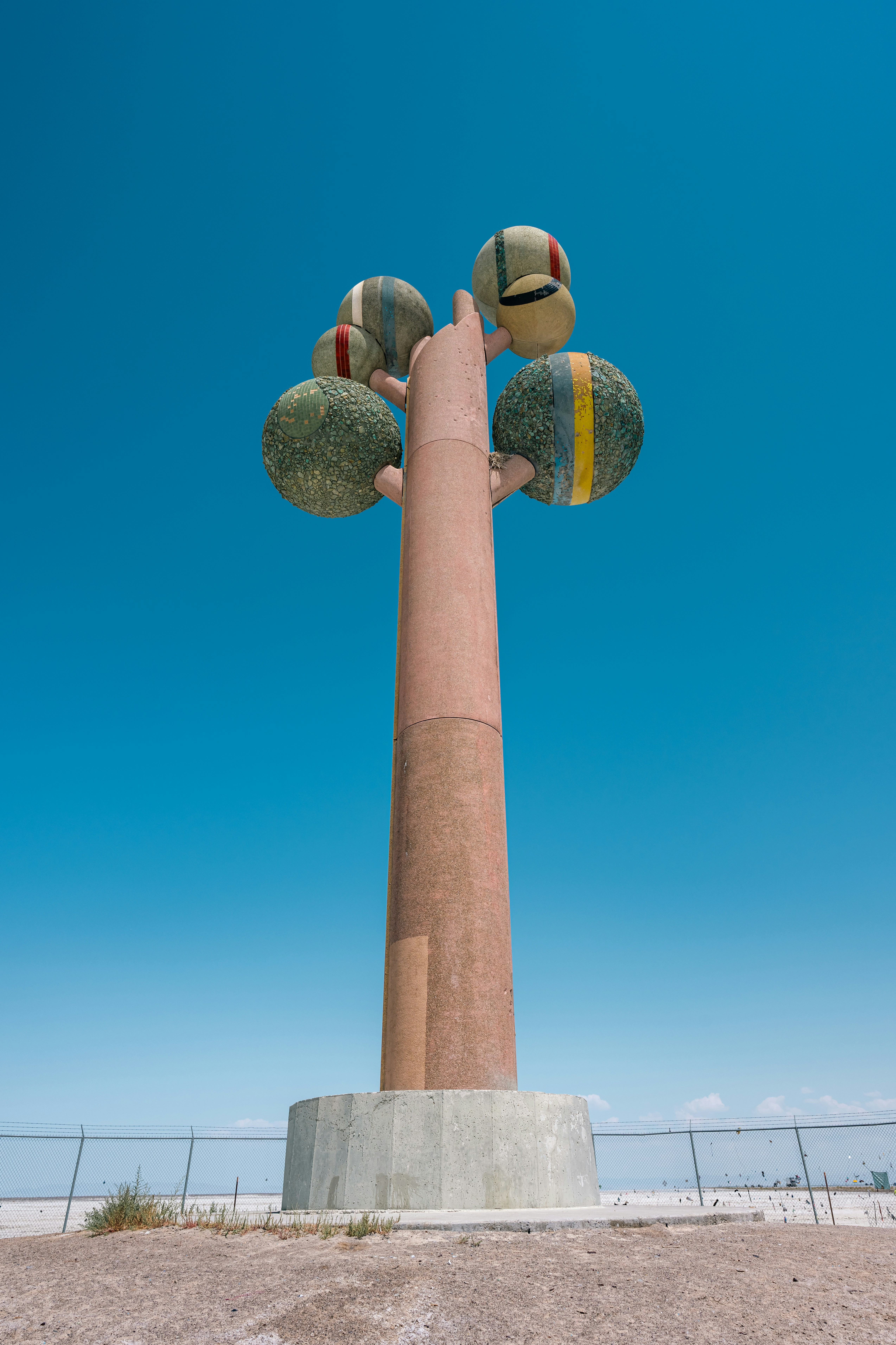 Tall abstract sculpture with spherical elements against blue sky