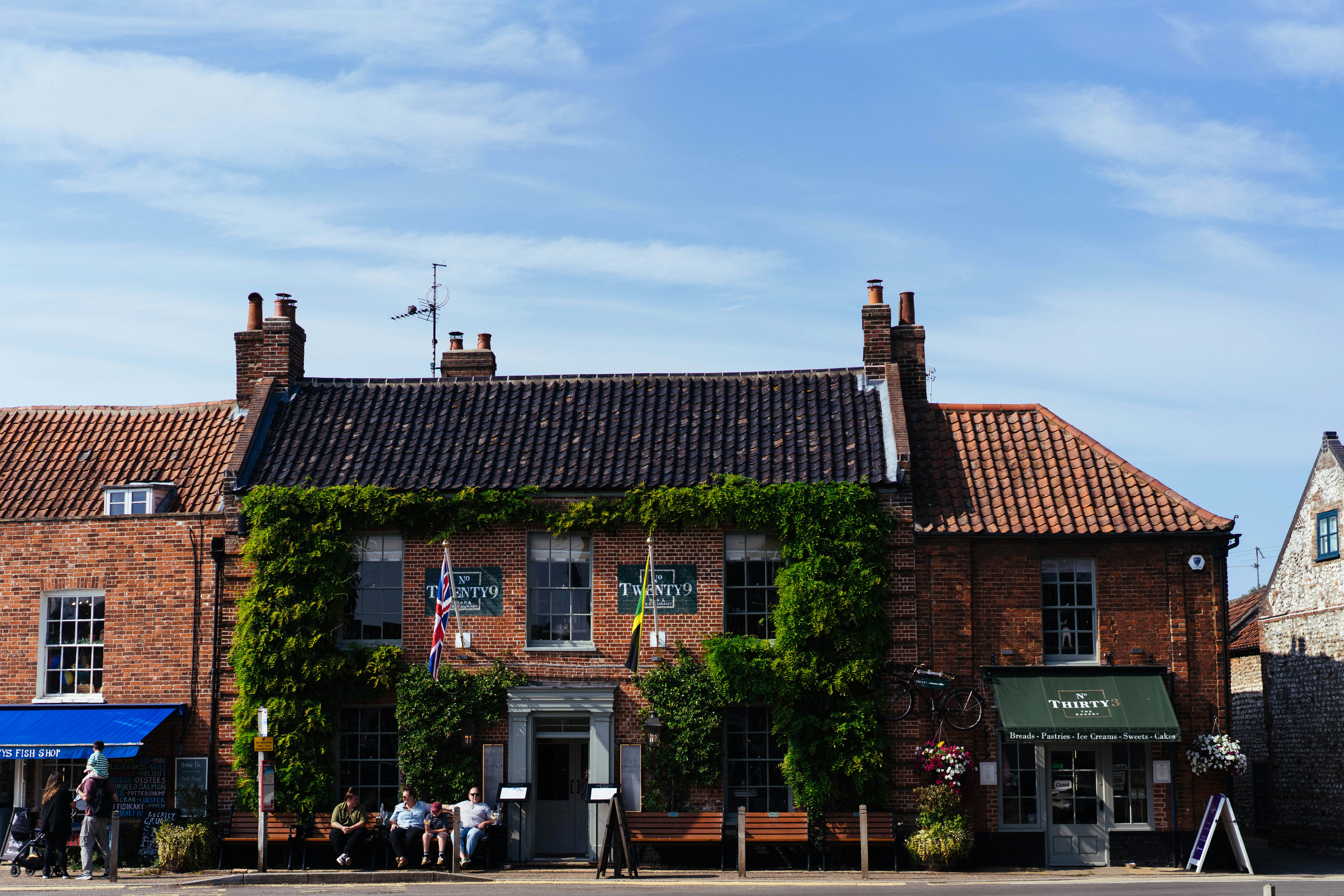 Brick buildings with green ivy and shops on a sunny day.