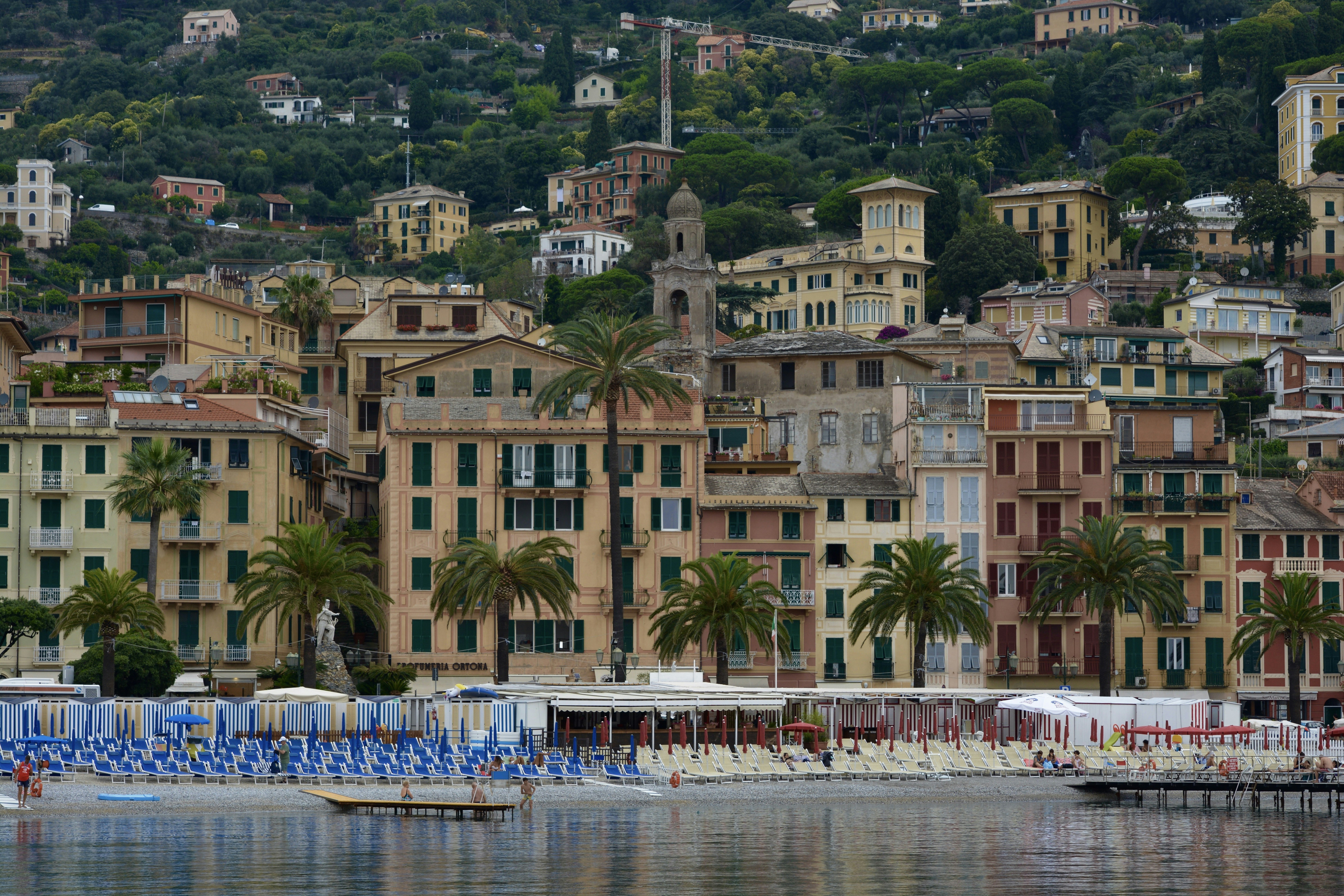 Colorful buildings line a waterfront with palm trees.