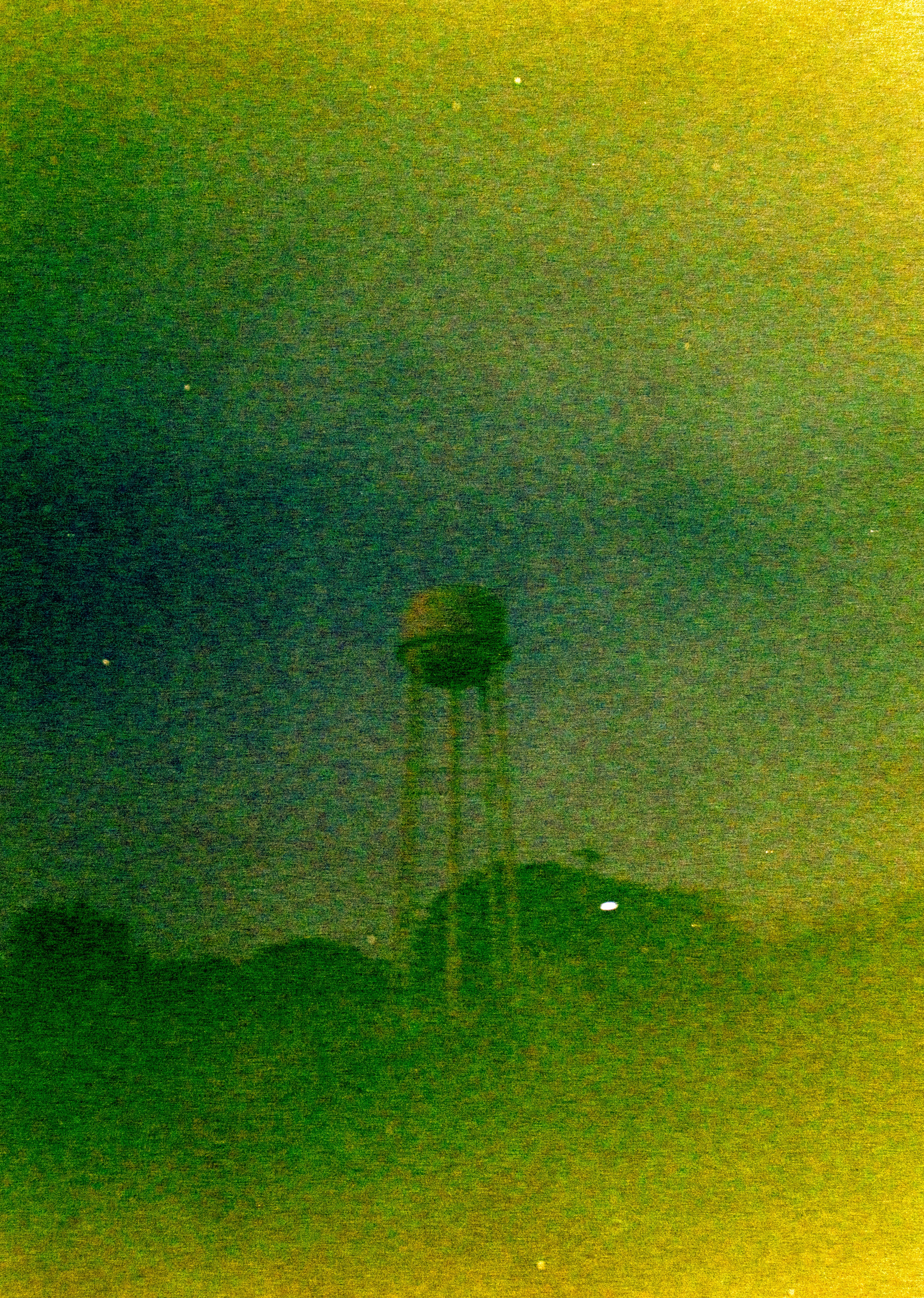 A weathered water tower stands silhouetted against a softly illuminated sky, capturing the essence of nostalgia and decay.