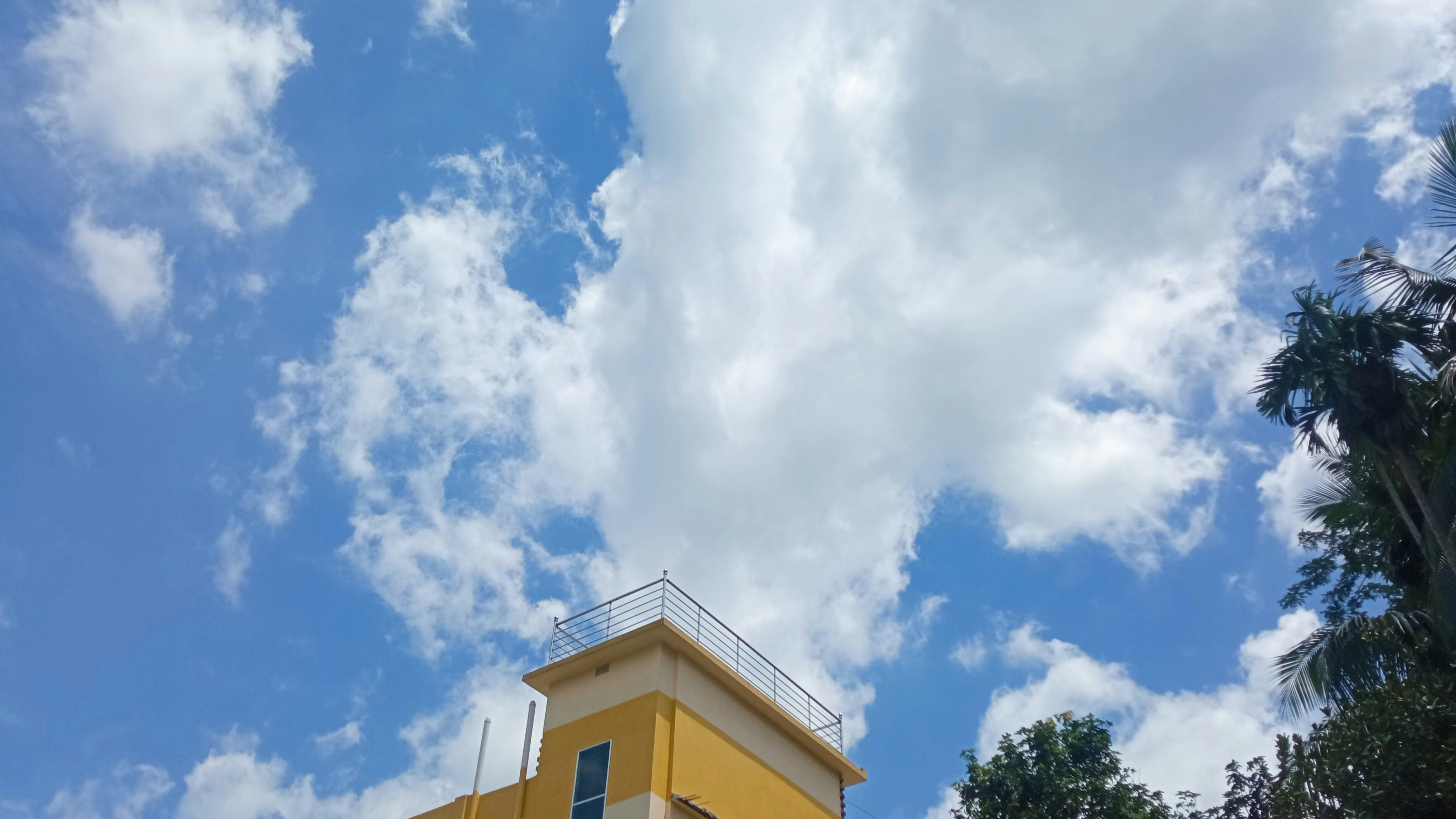 Yellow building under a cloudy blue sky.