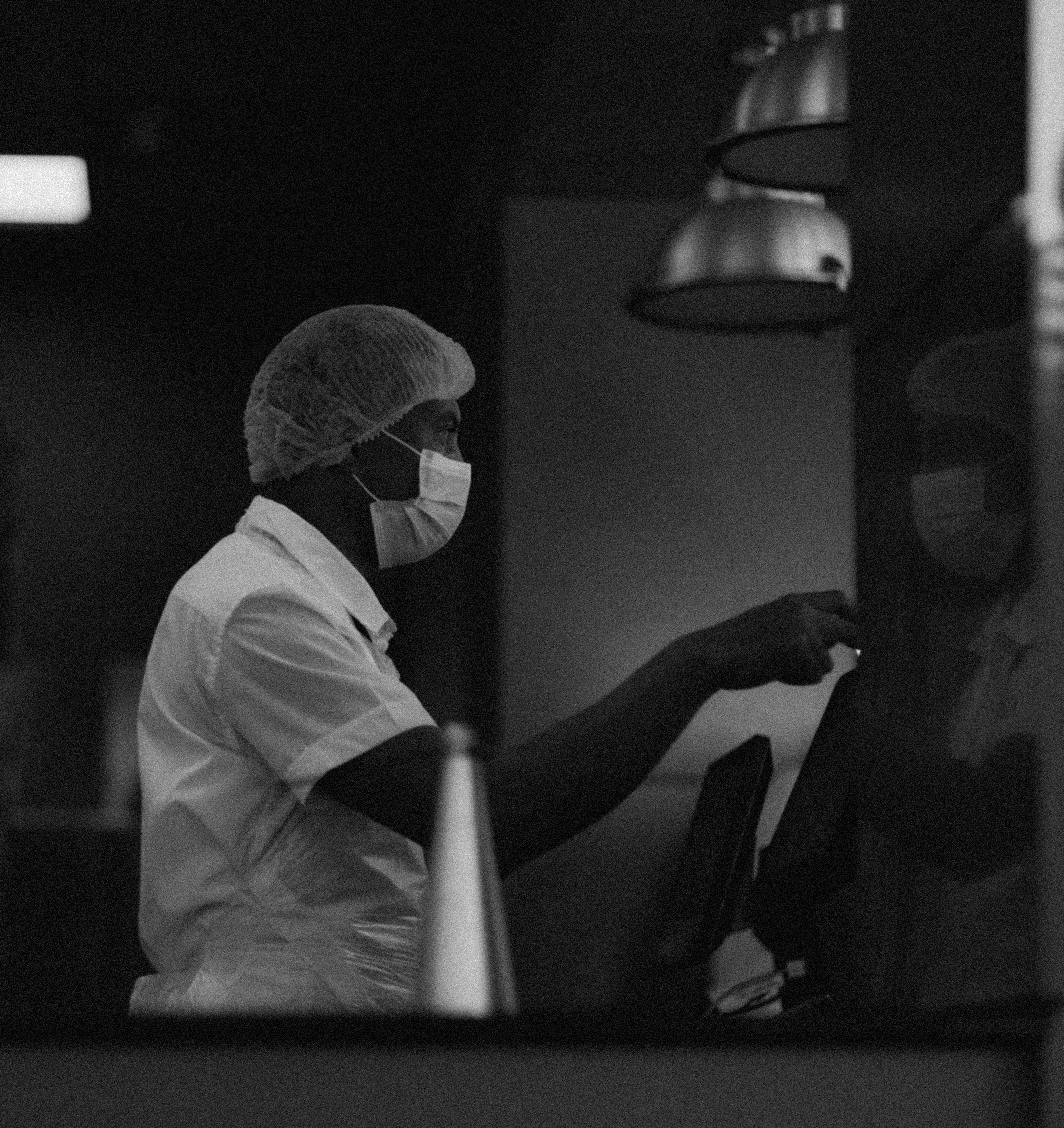 Worker in mask and hairnet points at screen