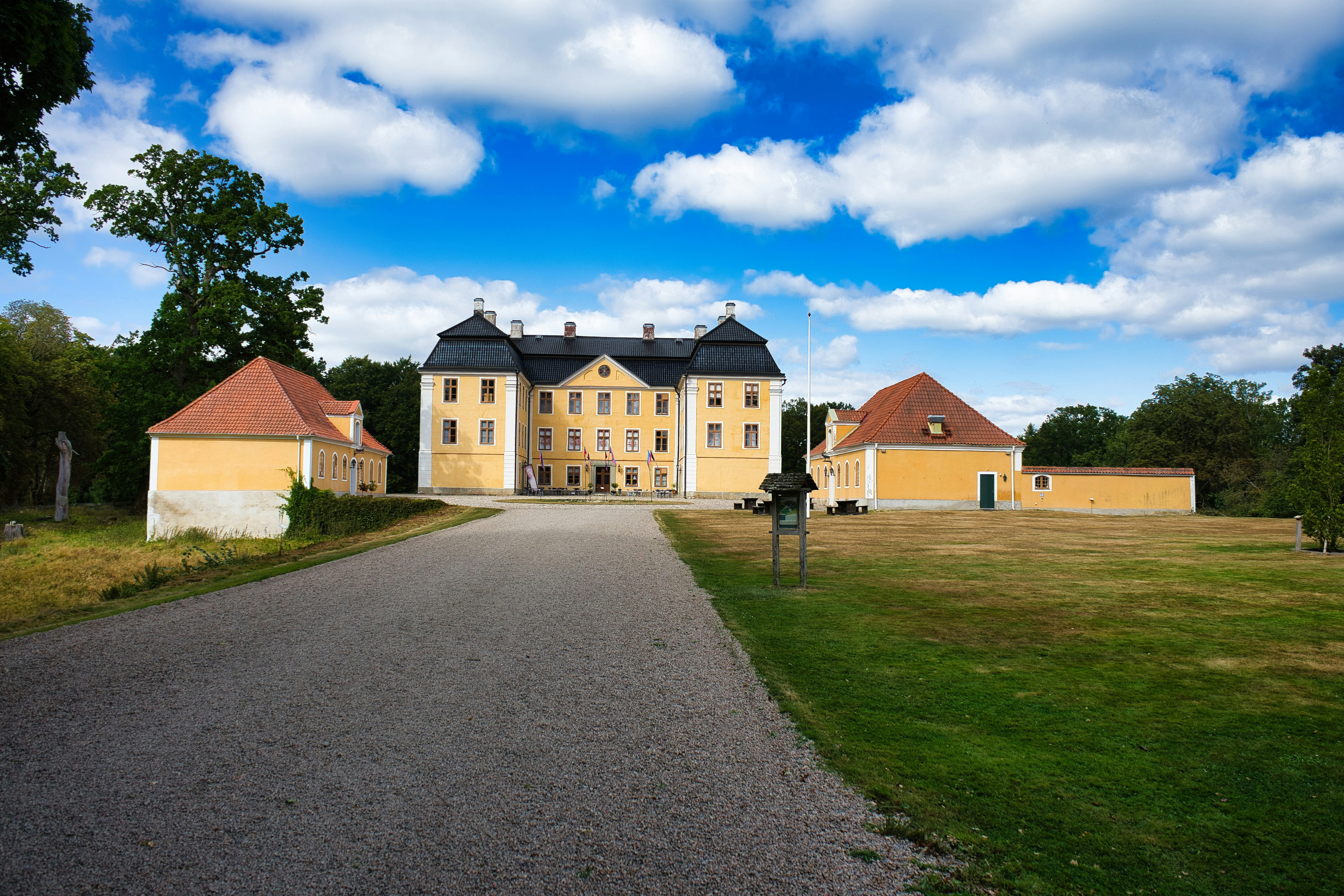 Christinehofs Castle | Yellow castle with a long driveway under blue sky.