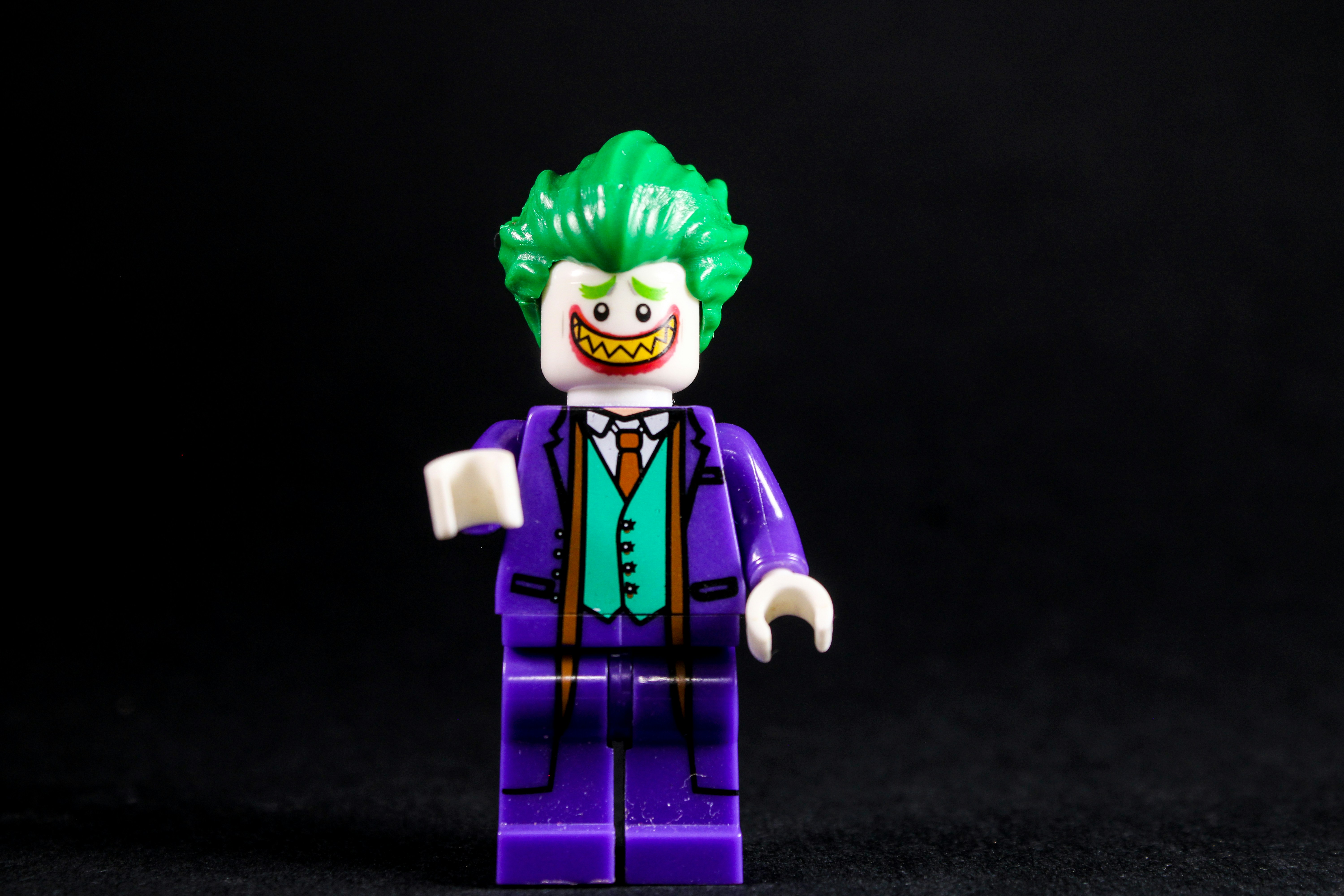 Lego Joker Standing Against a Black Background. | Lego joker figure with green hair and purple suit.