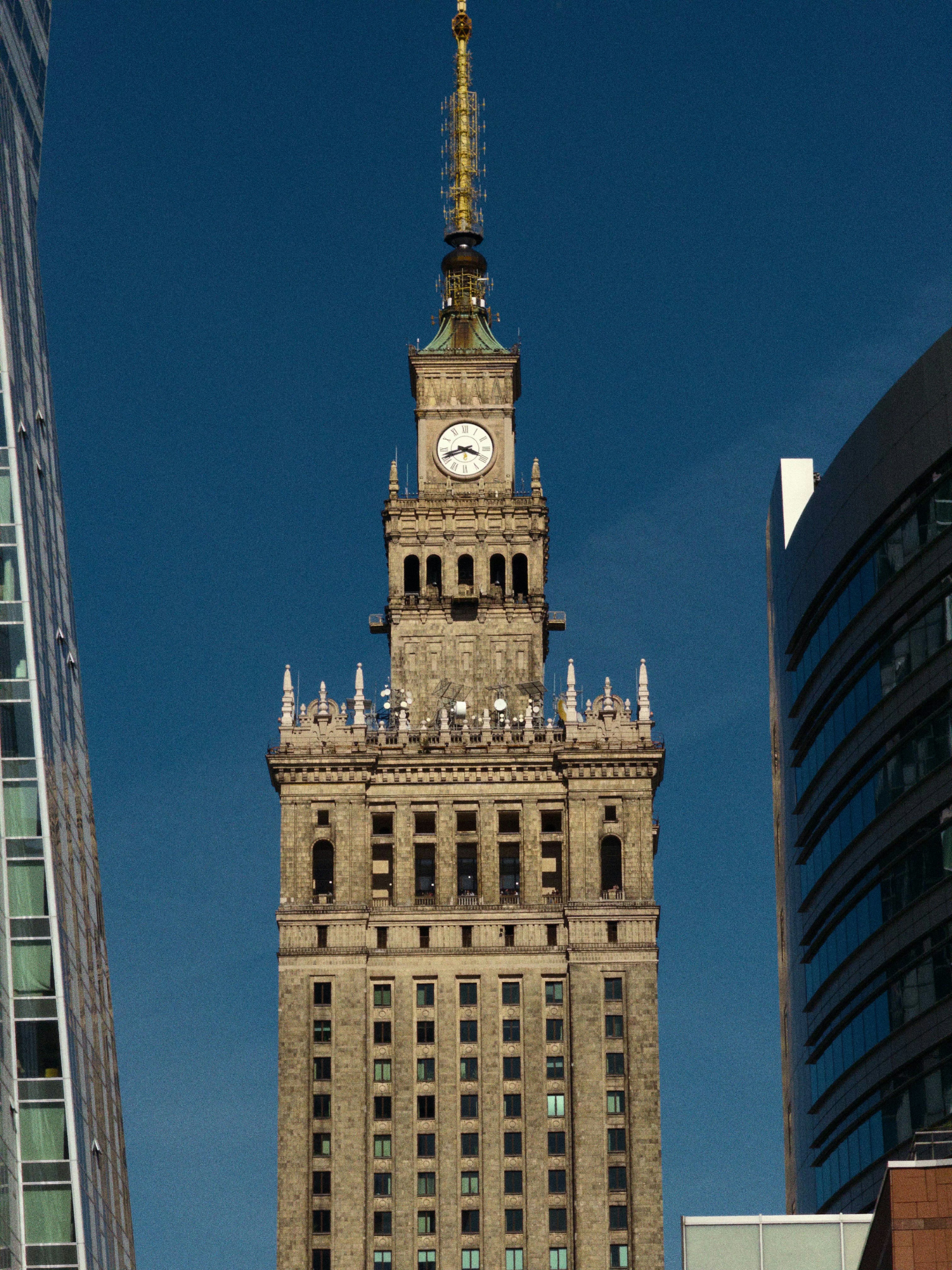 Tall historic building with clock tower between modern skyscrapers