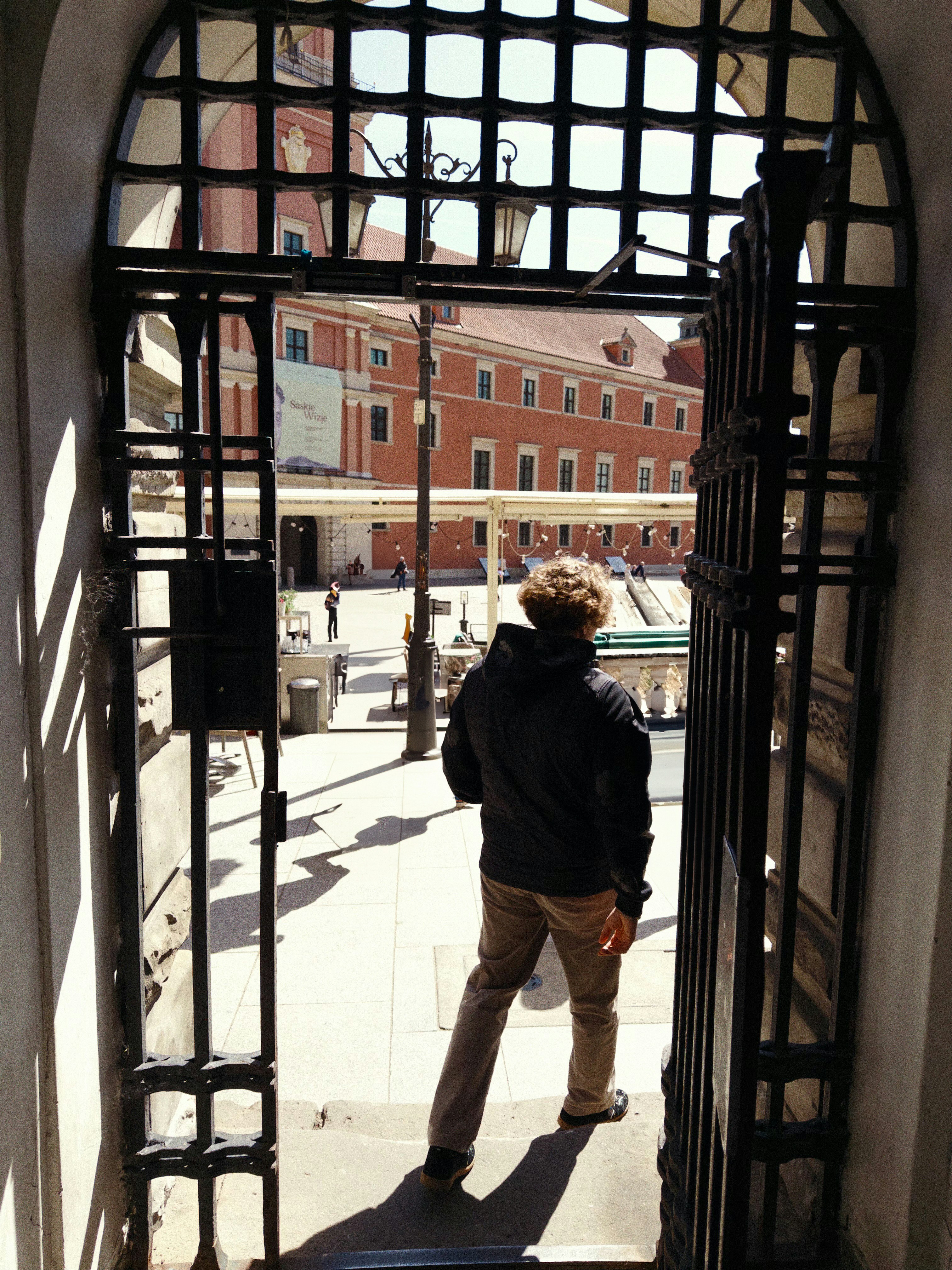 Man walks through an ornate doorway into a city square.