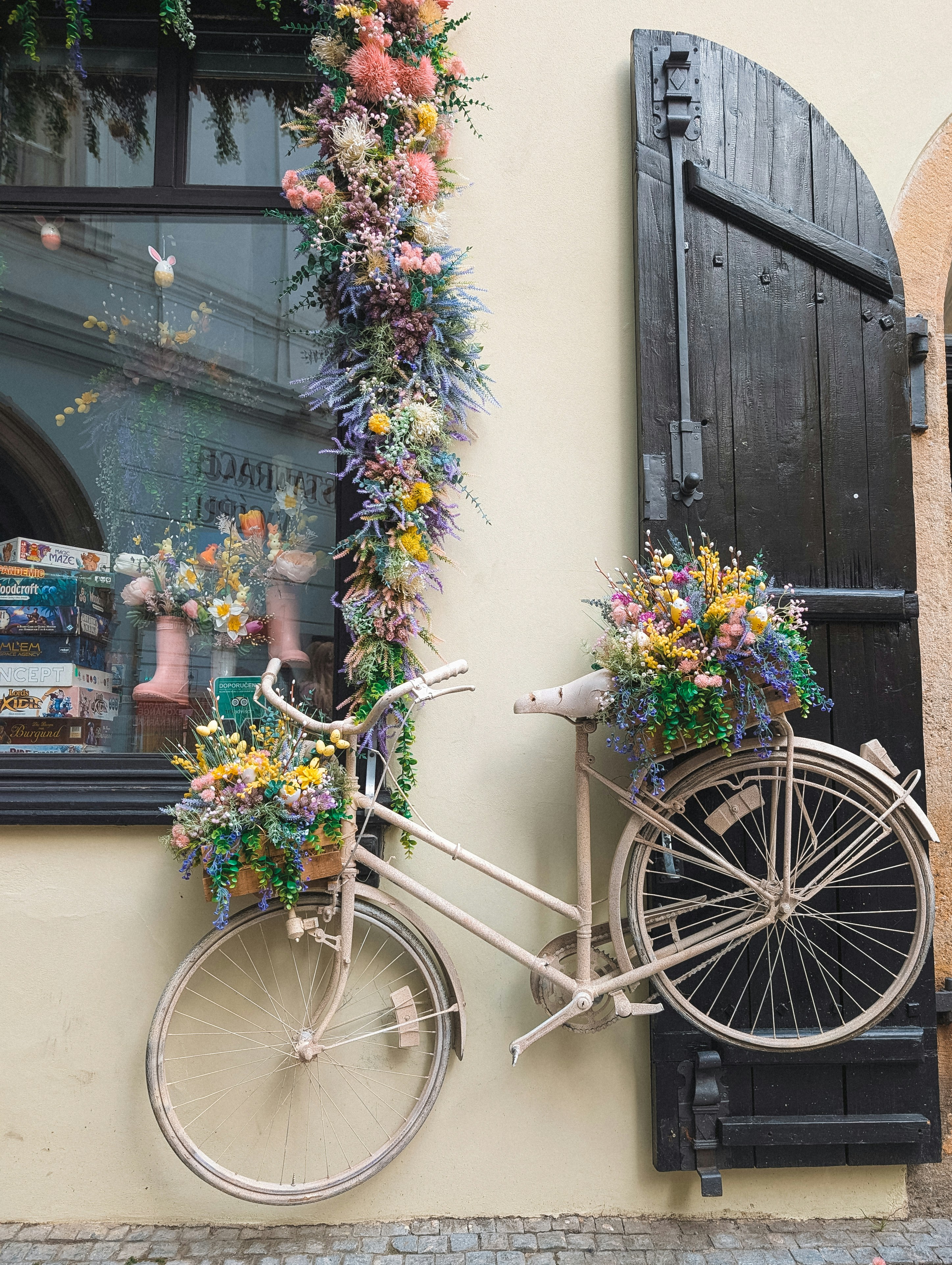 Vintage bicycle with flower baskets on a wall | Bicycle decorated with colorful flowers on a wall