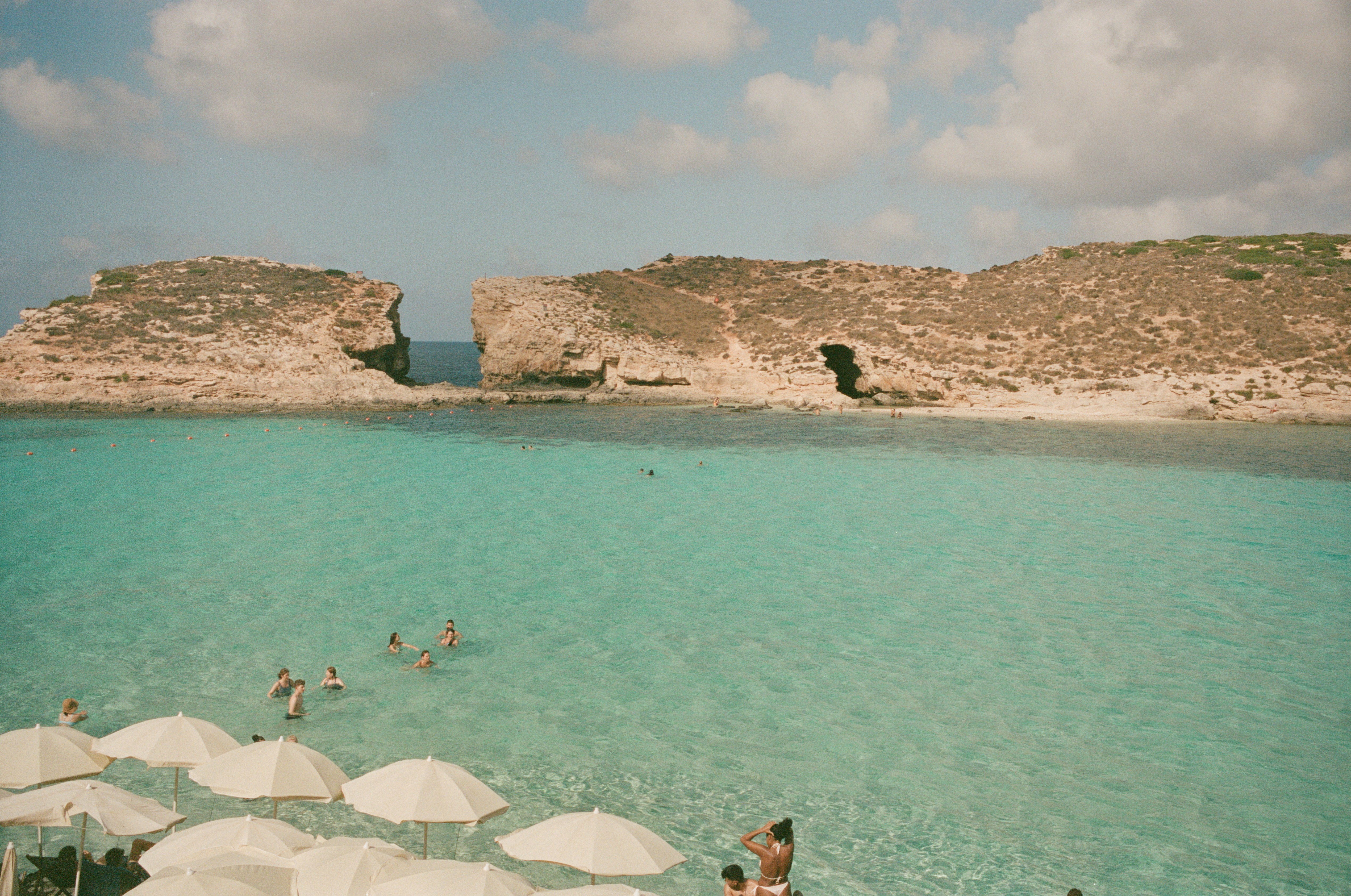 Summer midday at Blue Lagoon, Comino, Malta. Turquoise waters and limestone cliffs evoke tranquility.