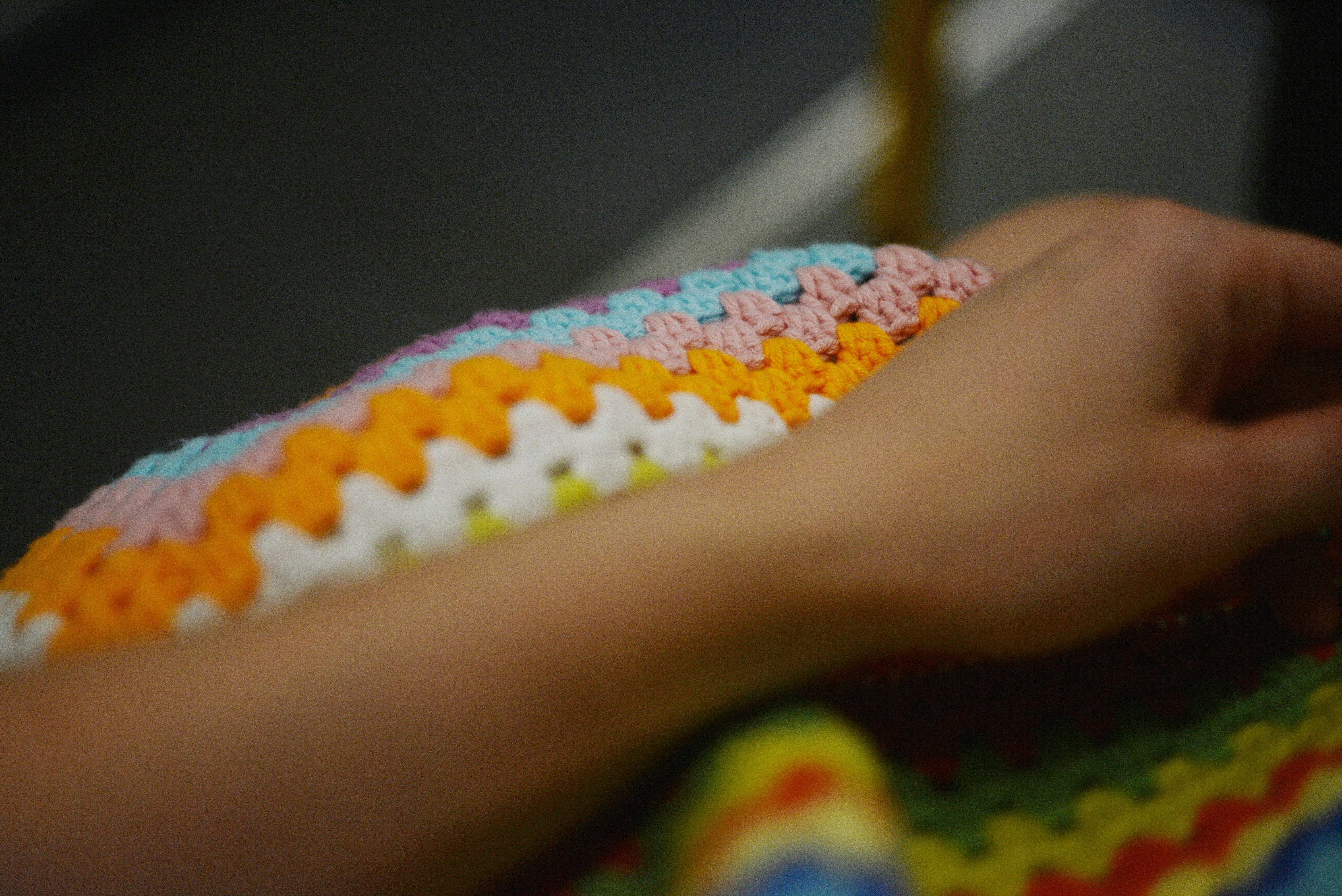 Hand resting on a colorful crocheted blanket.