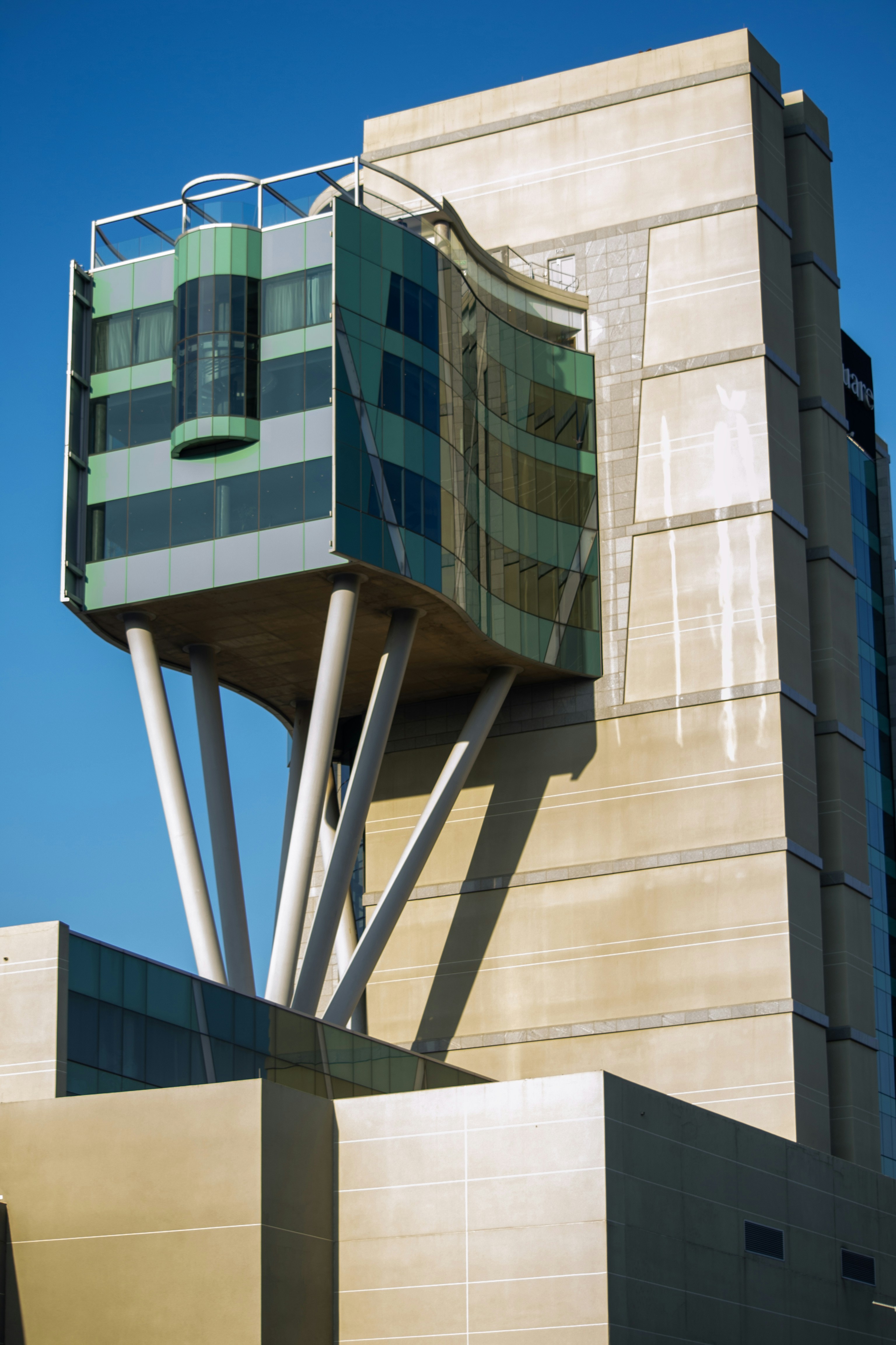 Elevated Glass Facade: A Structural Prow Pivoting Above Concrete Shadows