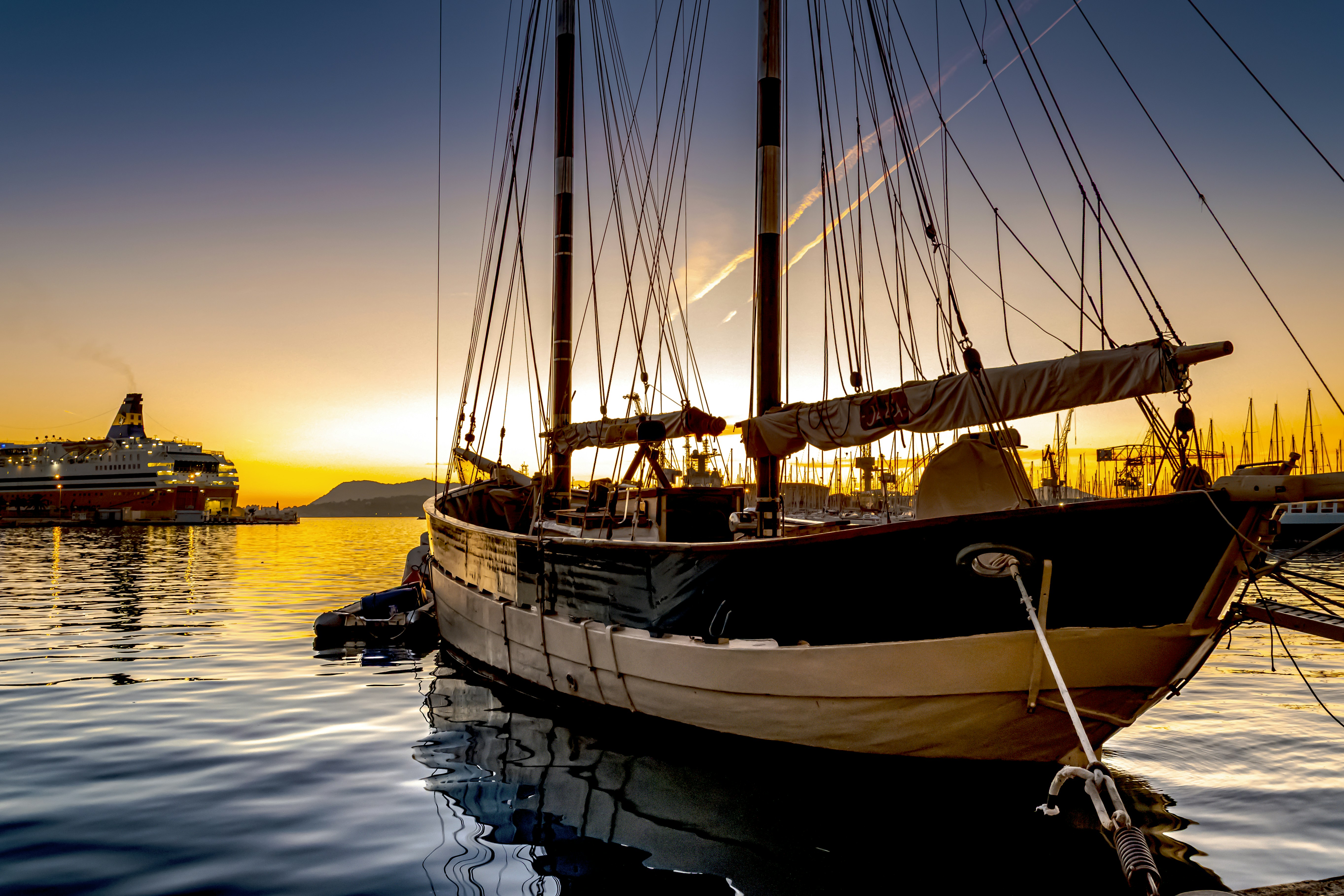 Sailboat docked in harbor at sunset
