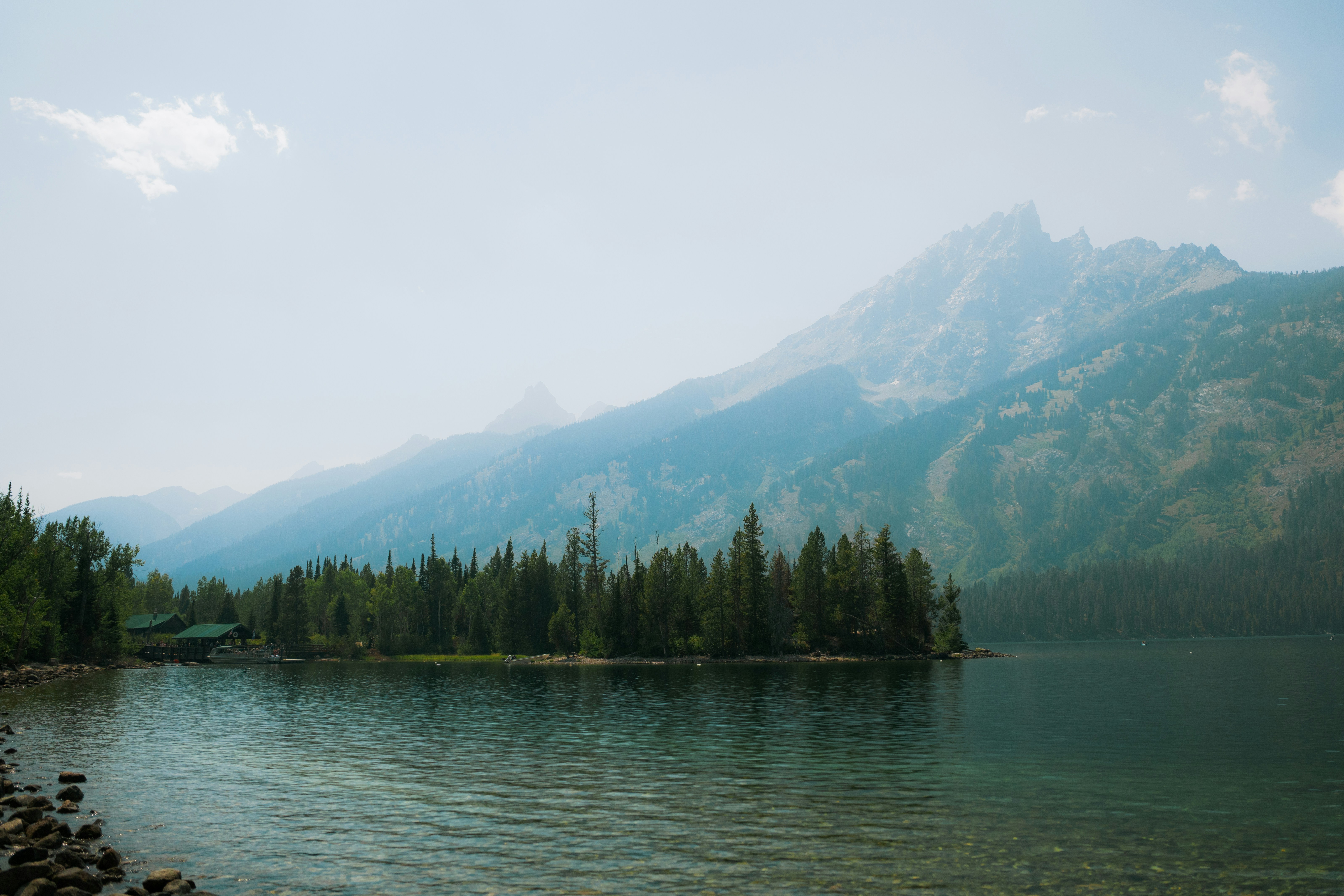 Tranquil lake surrounded by towering mountains and lush forests, capturing the essence of nature's calm. The scene invites contemplation and connection with the wilderness.
