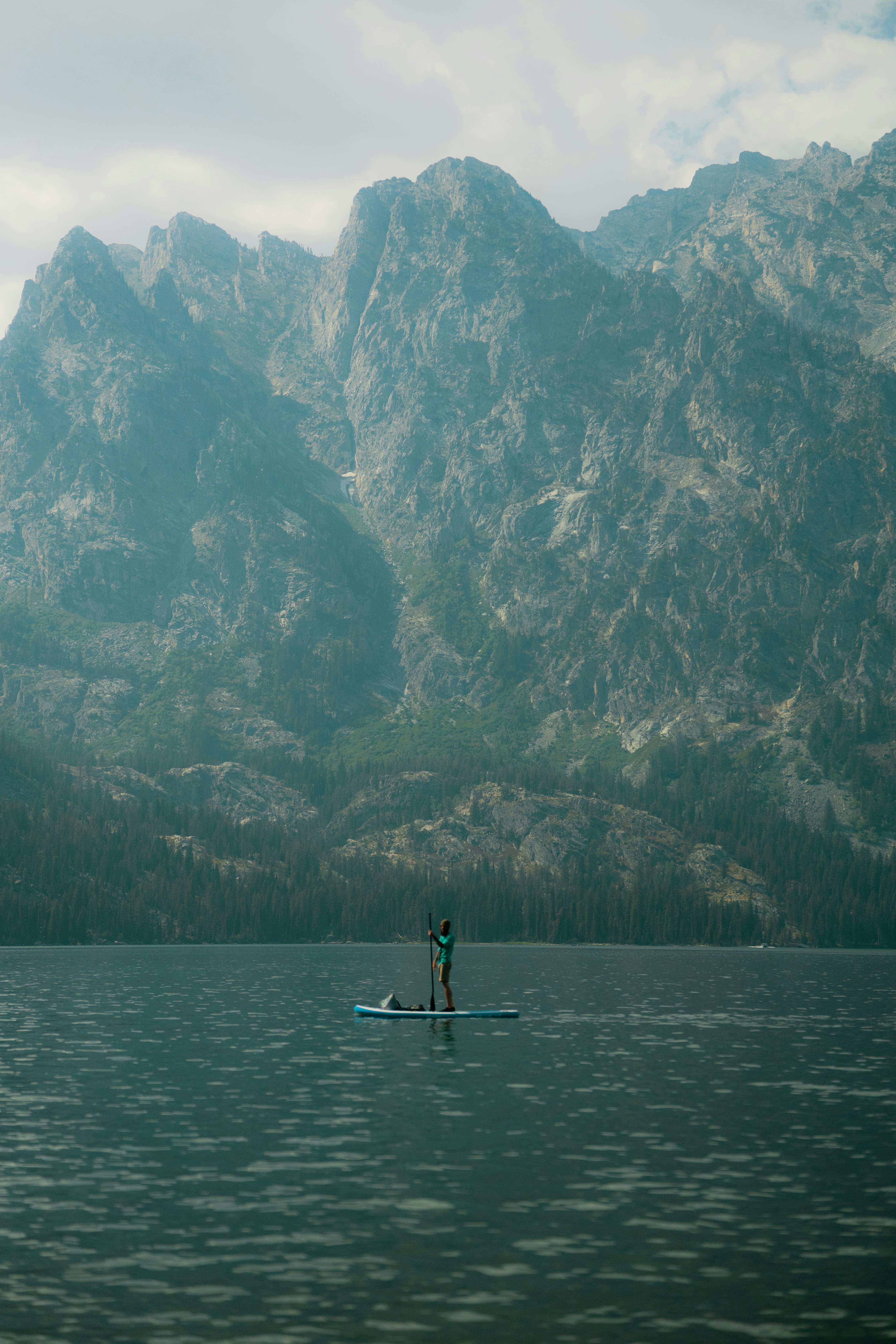 Person paddleboarding on a lake with mountains behind. photo – Free ...