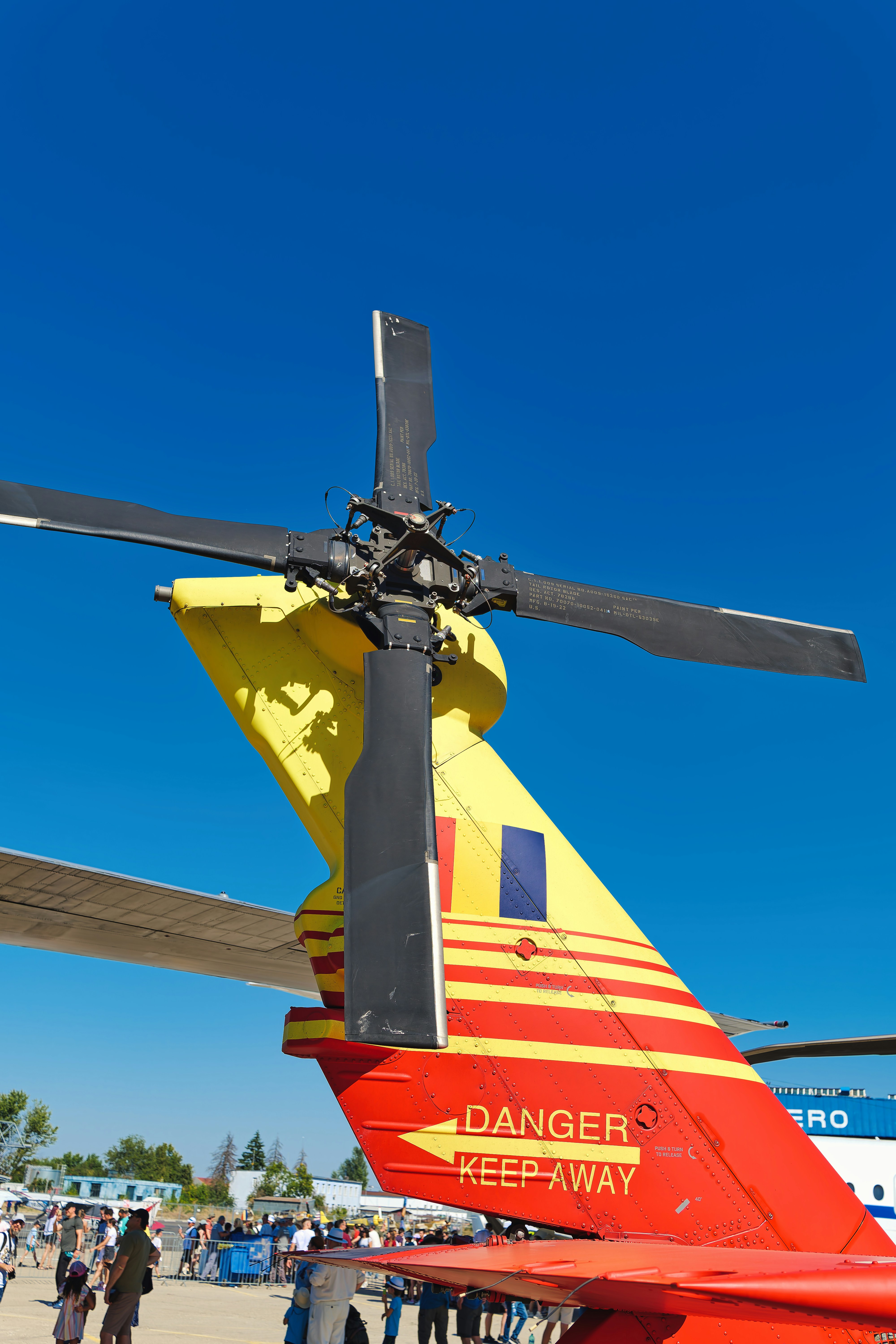 Cerulean Sky Framing a Bold Yellow-Red Helicopter Tail with 'Danger Keep Away' Markings