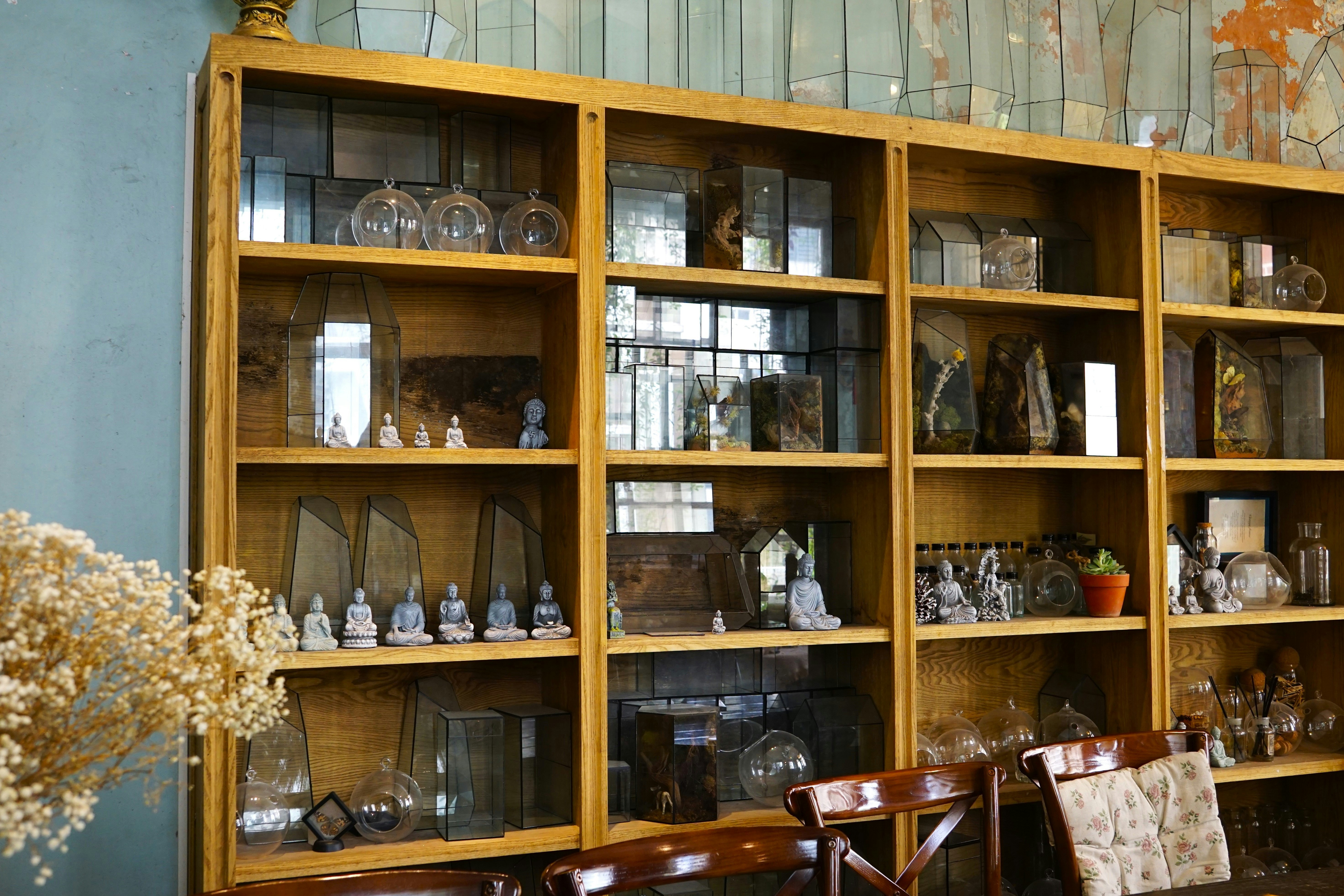 A wooden shelving unit showcases an array of glass objects and decorative pieces, creating a serene ambiance. The soft lighting enhances the details of each item.