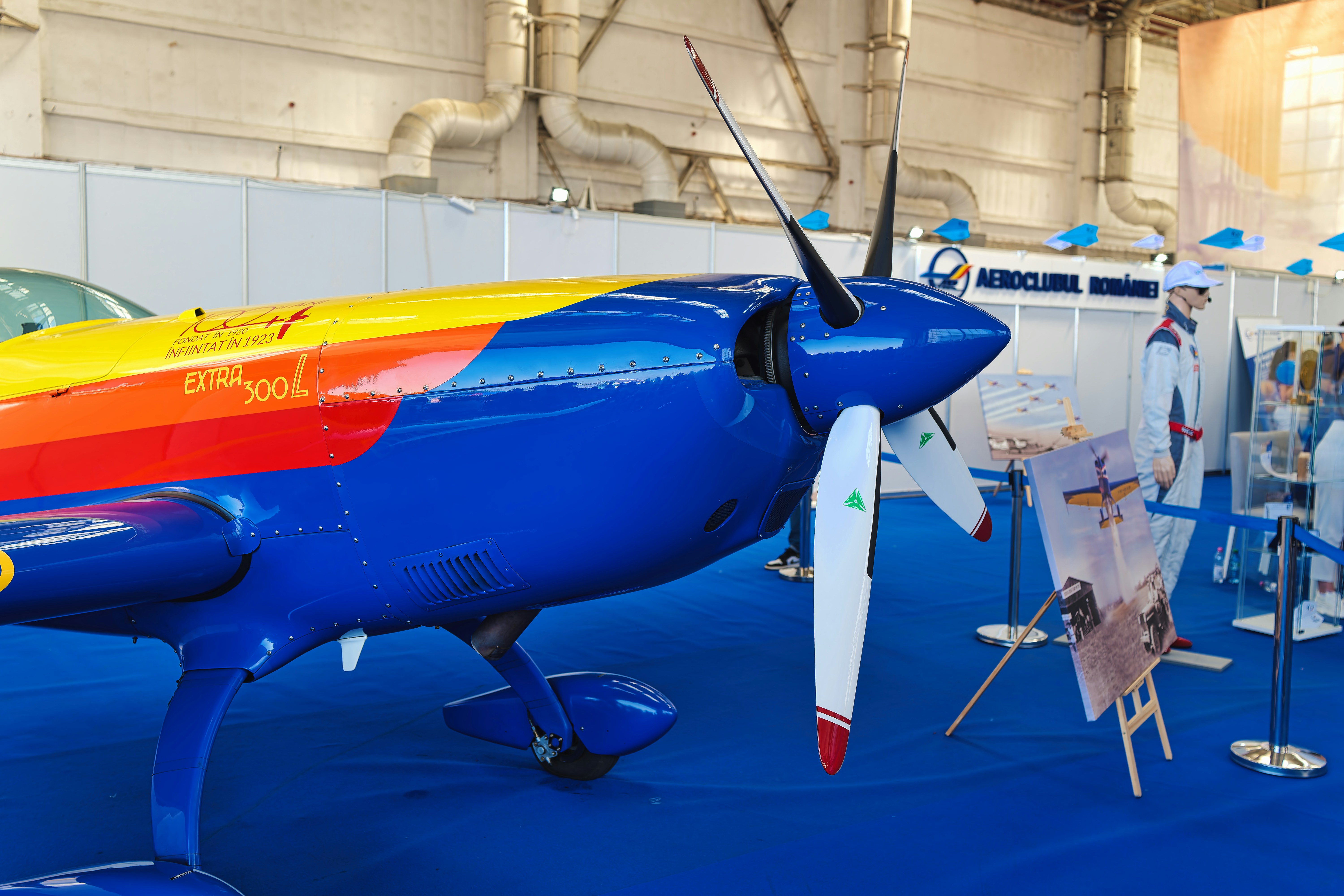 Rainbow-Striped Blue Aeroplane on an Indoor Aviation Exhibition Floor