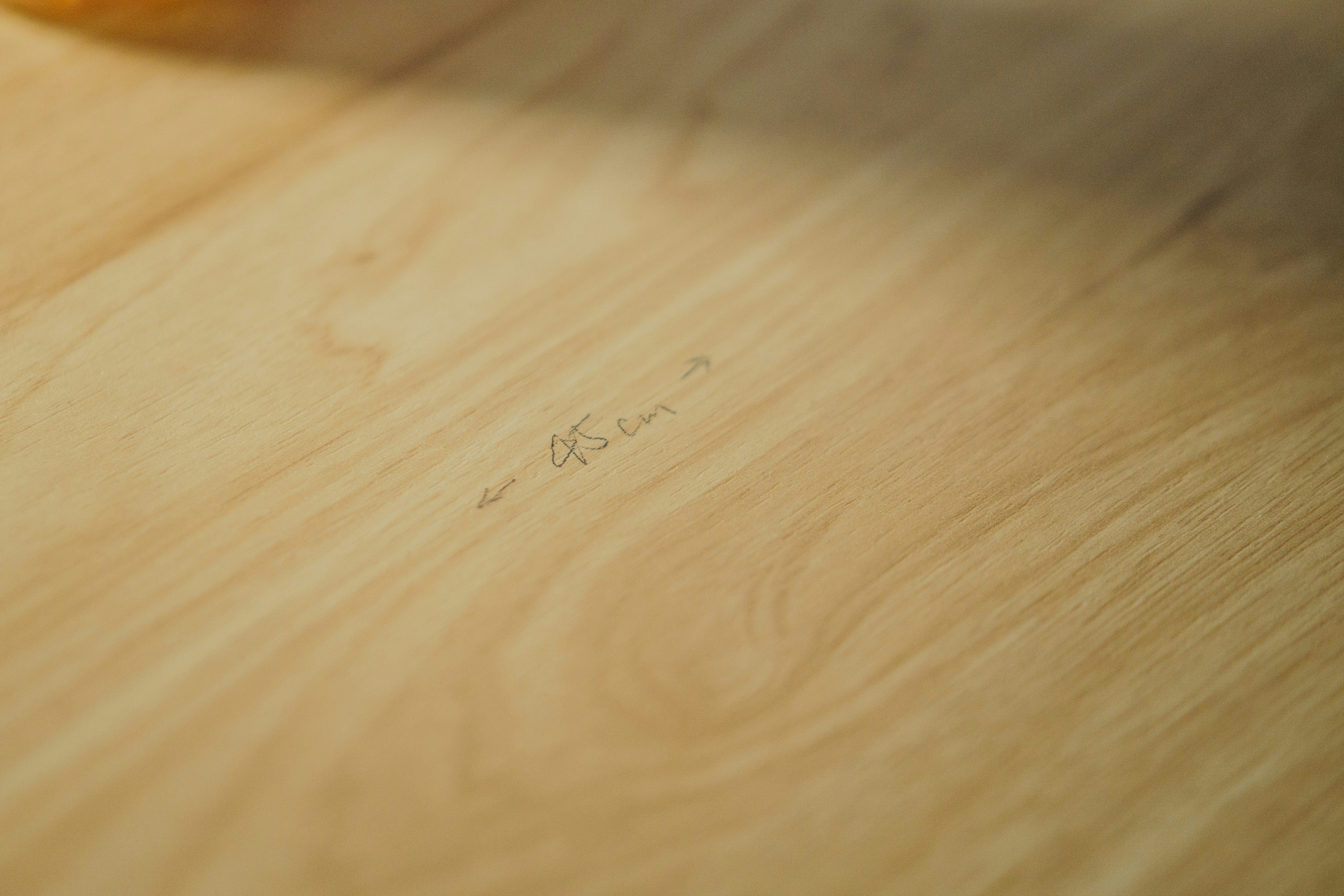 Close-up of faint writing on a wooden surface.