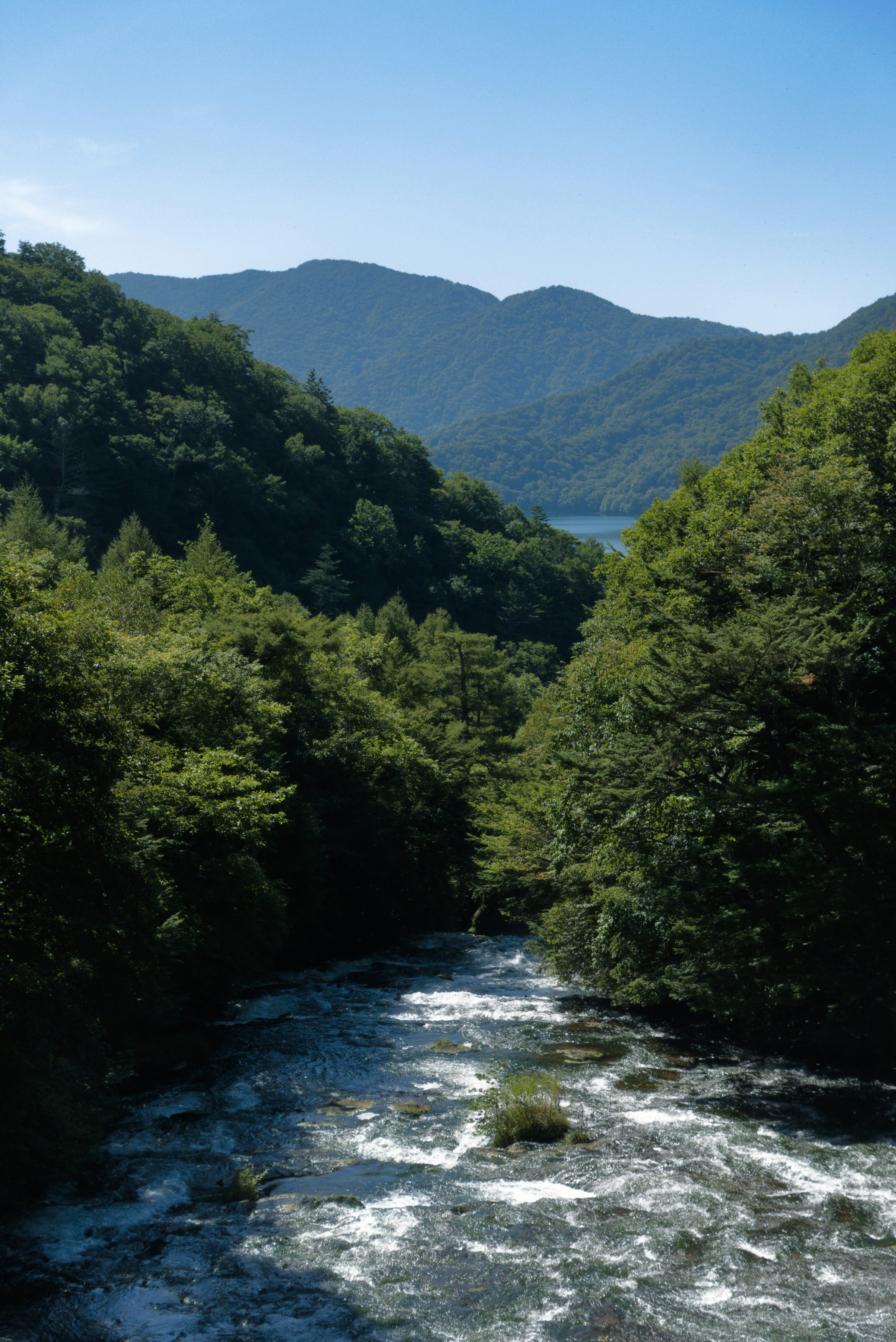 Chuzenki lake from Ryuzu cascades | River flowing through lush green forest towards mountains